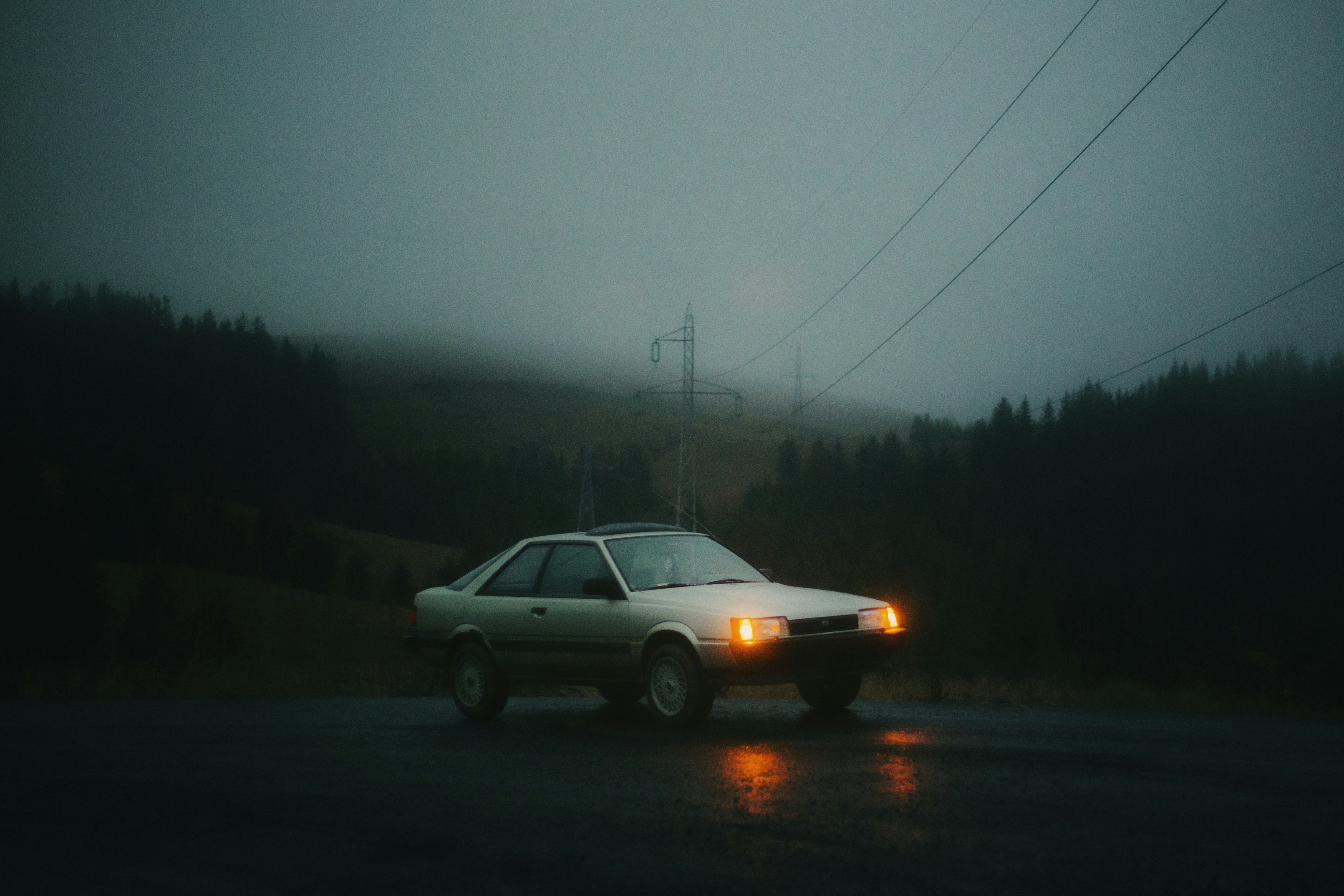 Headlights Through Rain: A Quiet Drive Beneath Power Lines