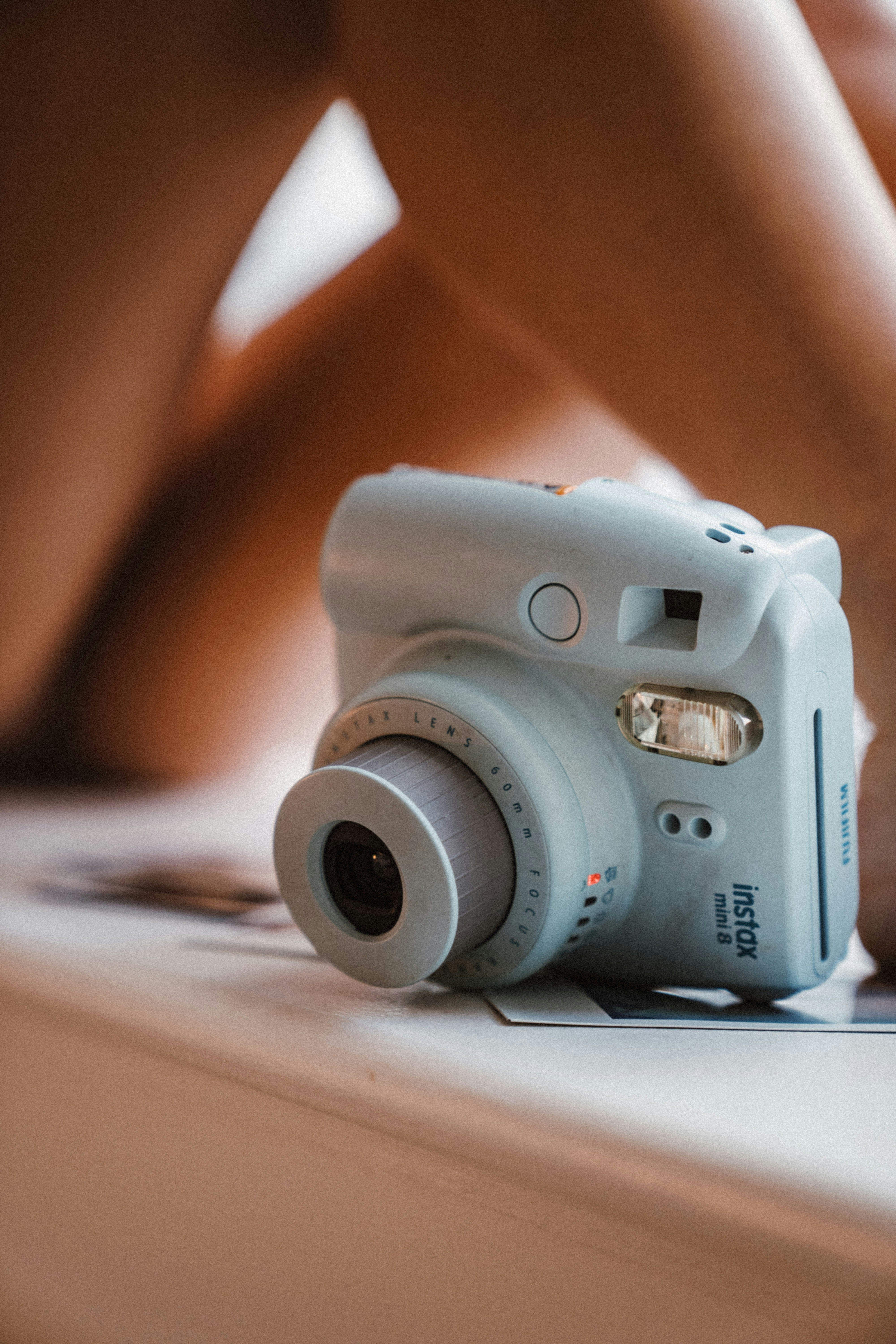 A pastel blue instant camera rests on a surface, surrounded by printed photos, evoking a sense of nostalgia and creativity.