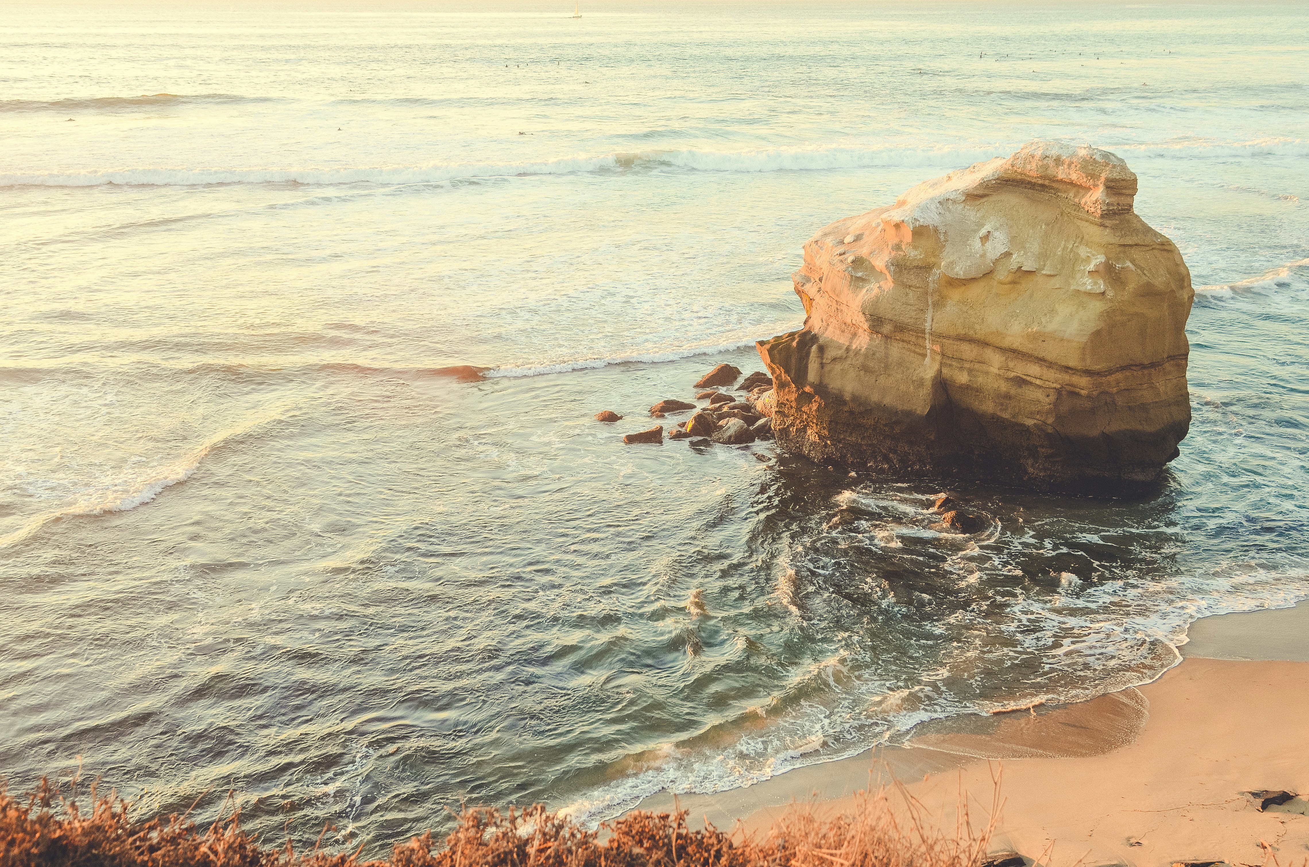 Un gros rocher sortant de l’océan à côté d’une plage photo – Image ...