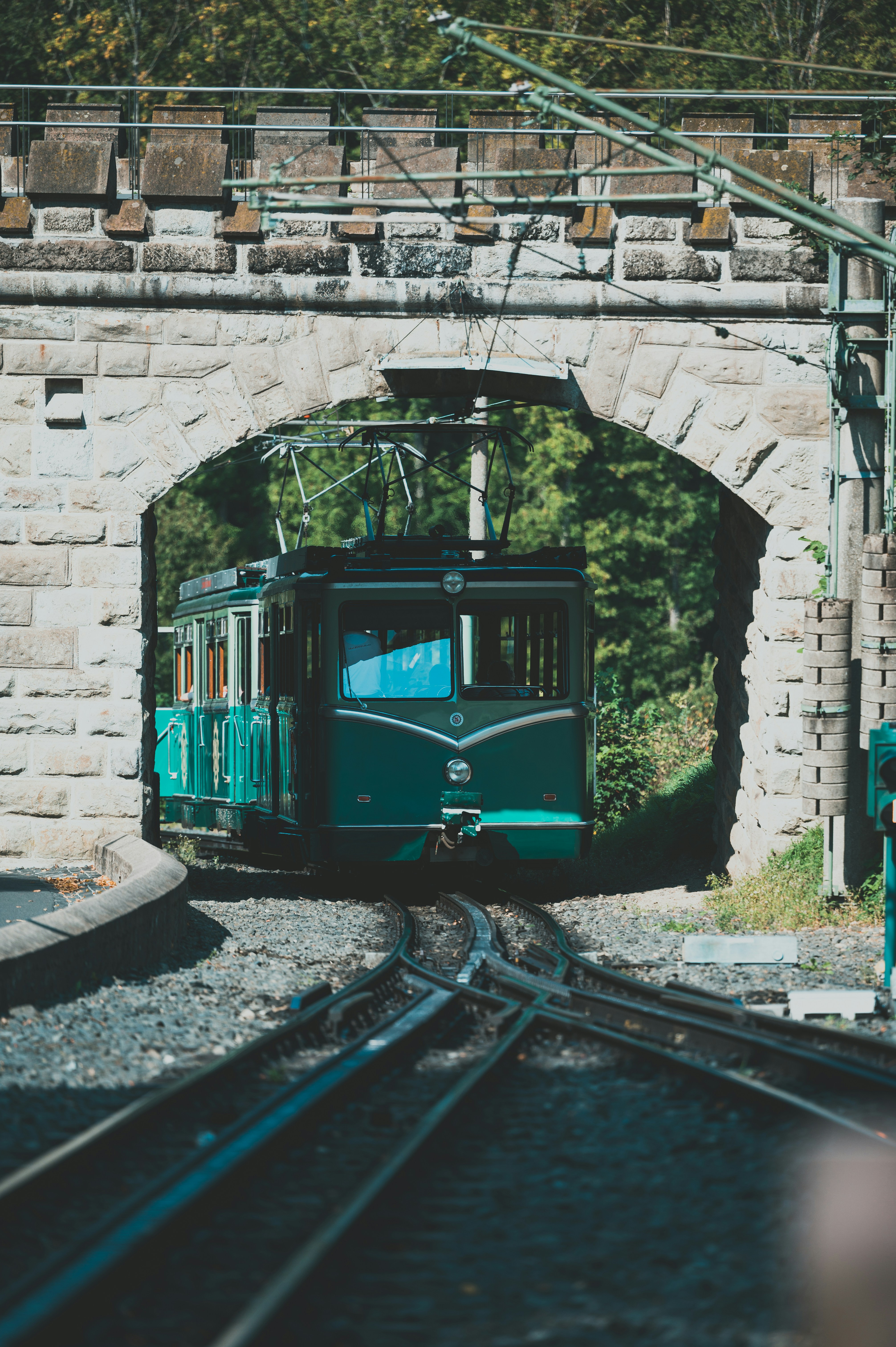 Green Tram Emerging Through the Stone Arch