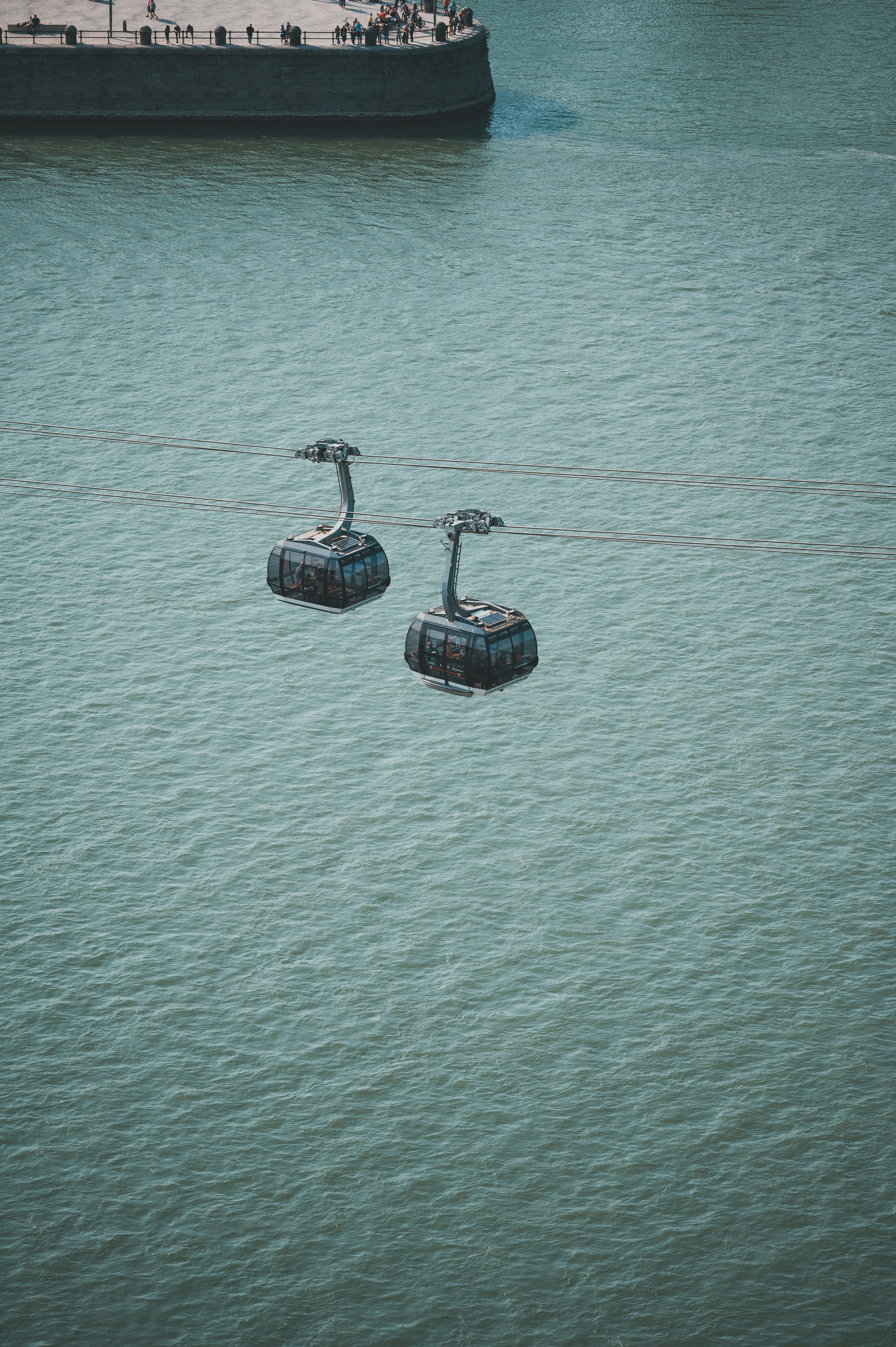 Twin Cable Cars Skim Over a Quiet Turquoise Harbor