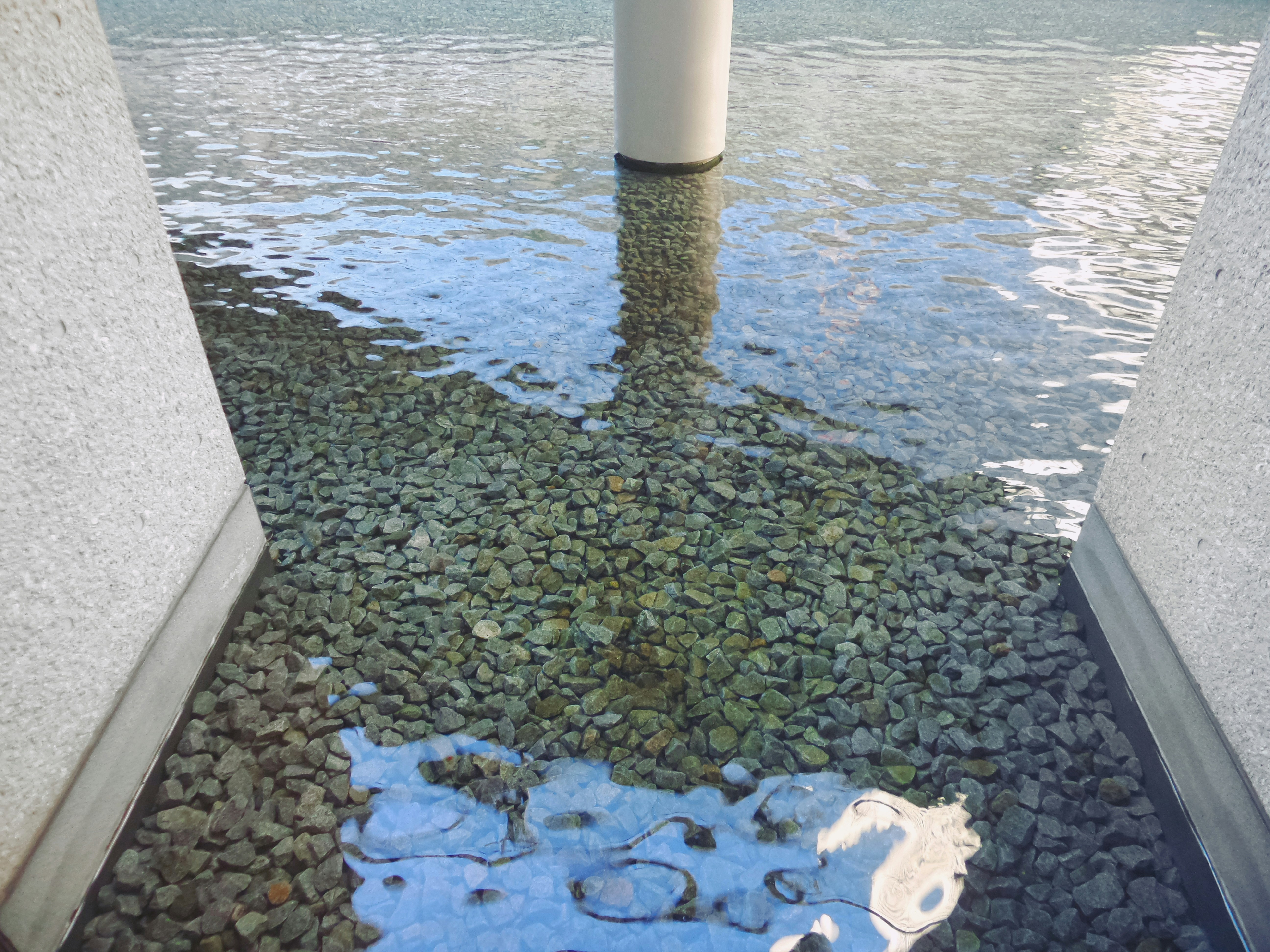 Between Concrete Pillars: A Quiet Pebble Pool Reflecting the Sky
