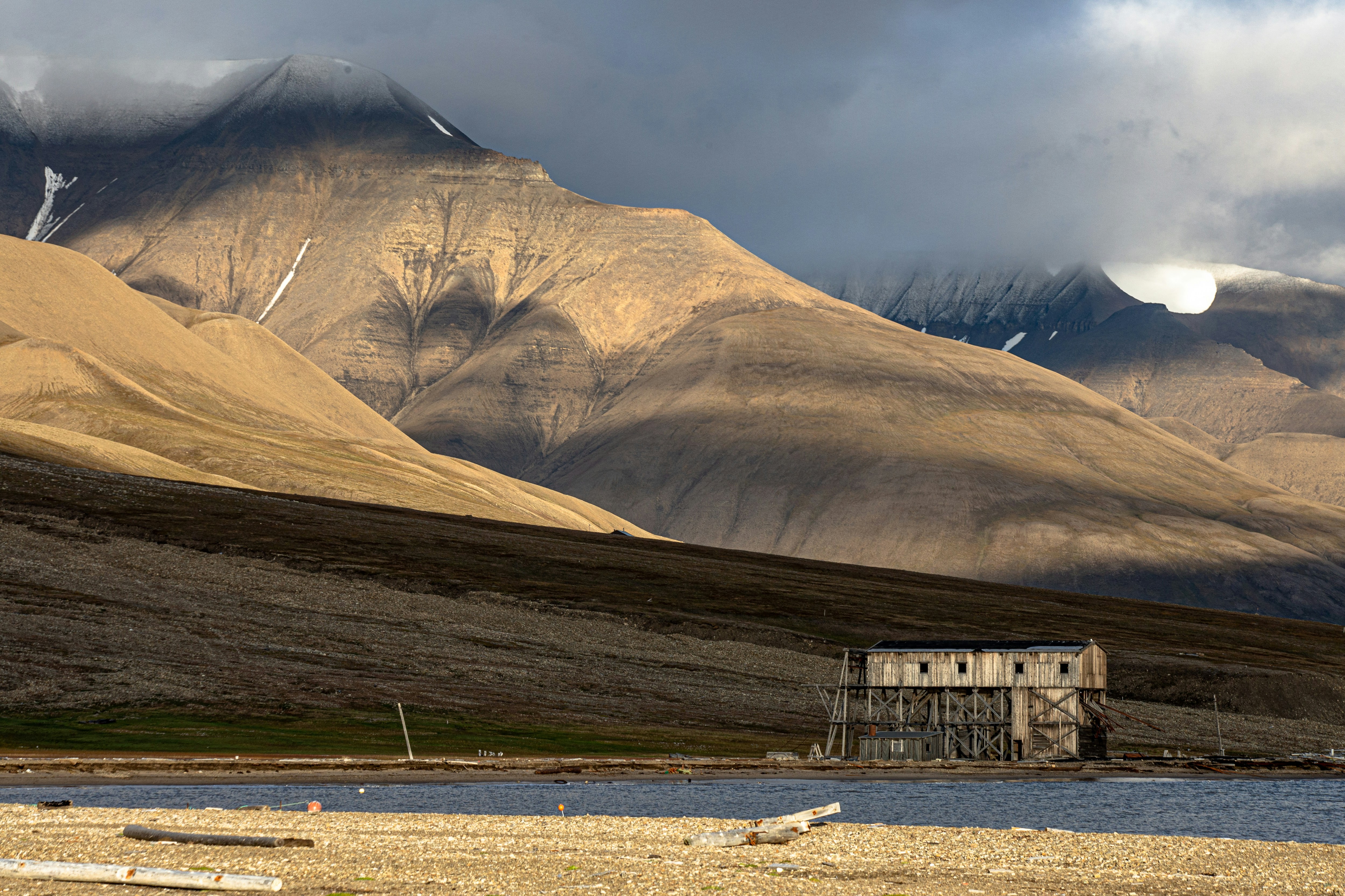 Weathered Outpost Beneath Storm-Burnished Peaks at Golden Hour