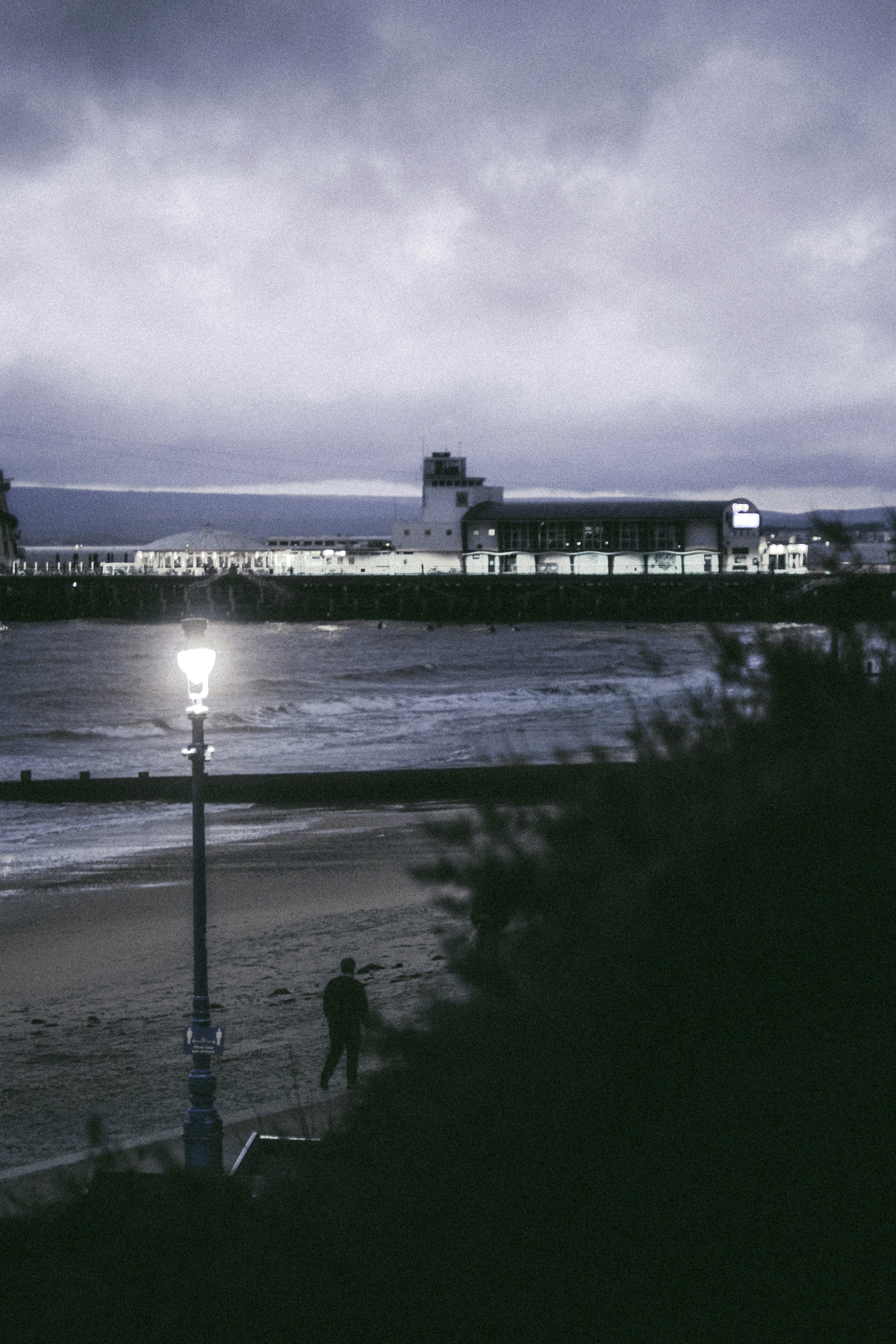 man in black jacket walking on seashore during night time