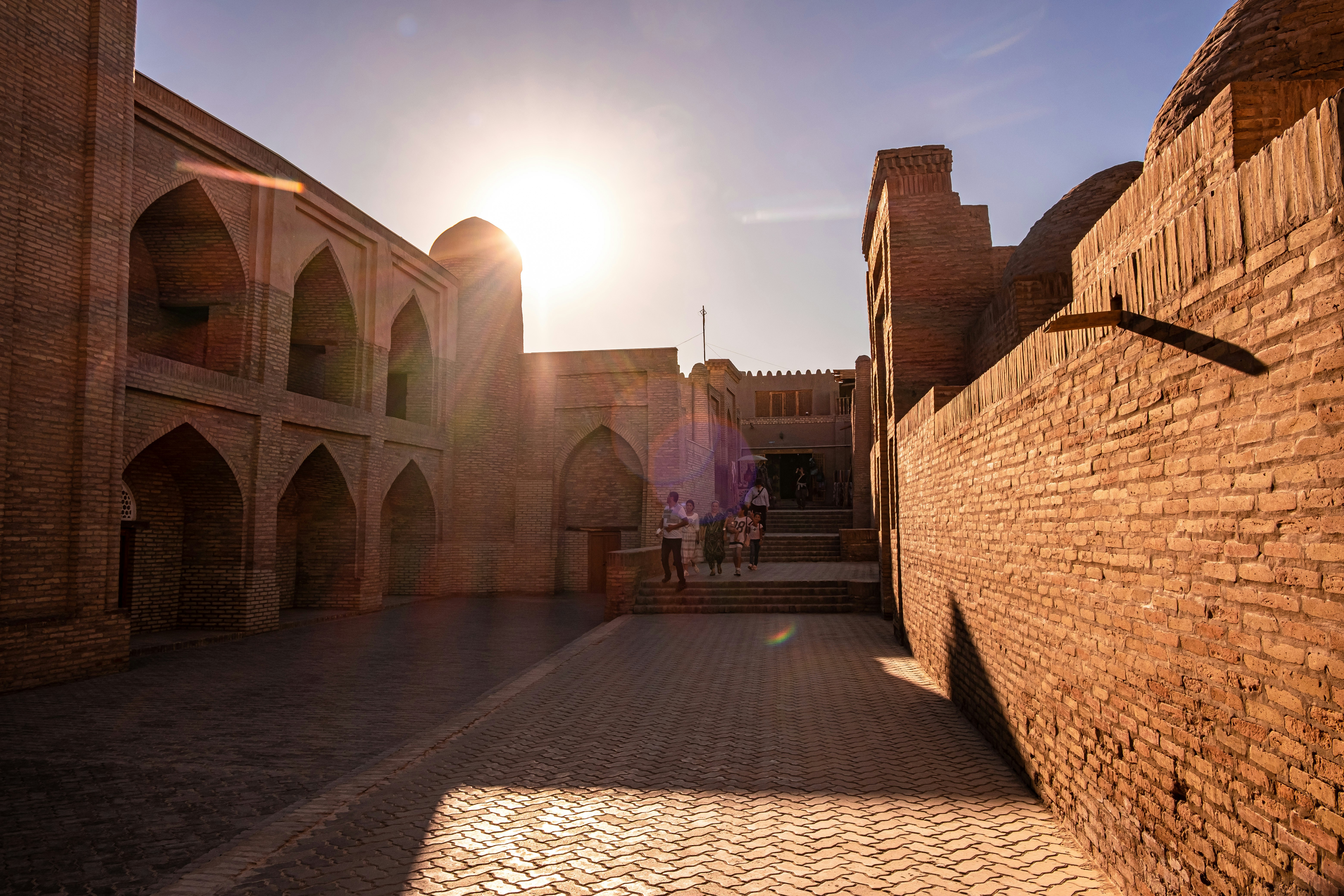 Sunlit Brick Courtyard: Arches Framing a Quiet Crowd at the Steps