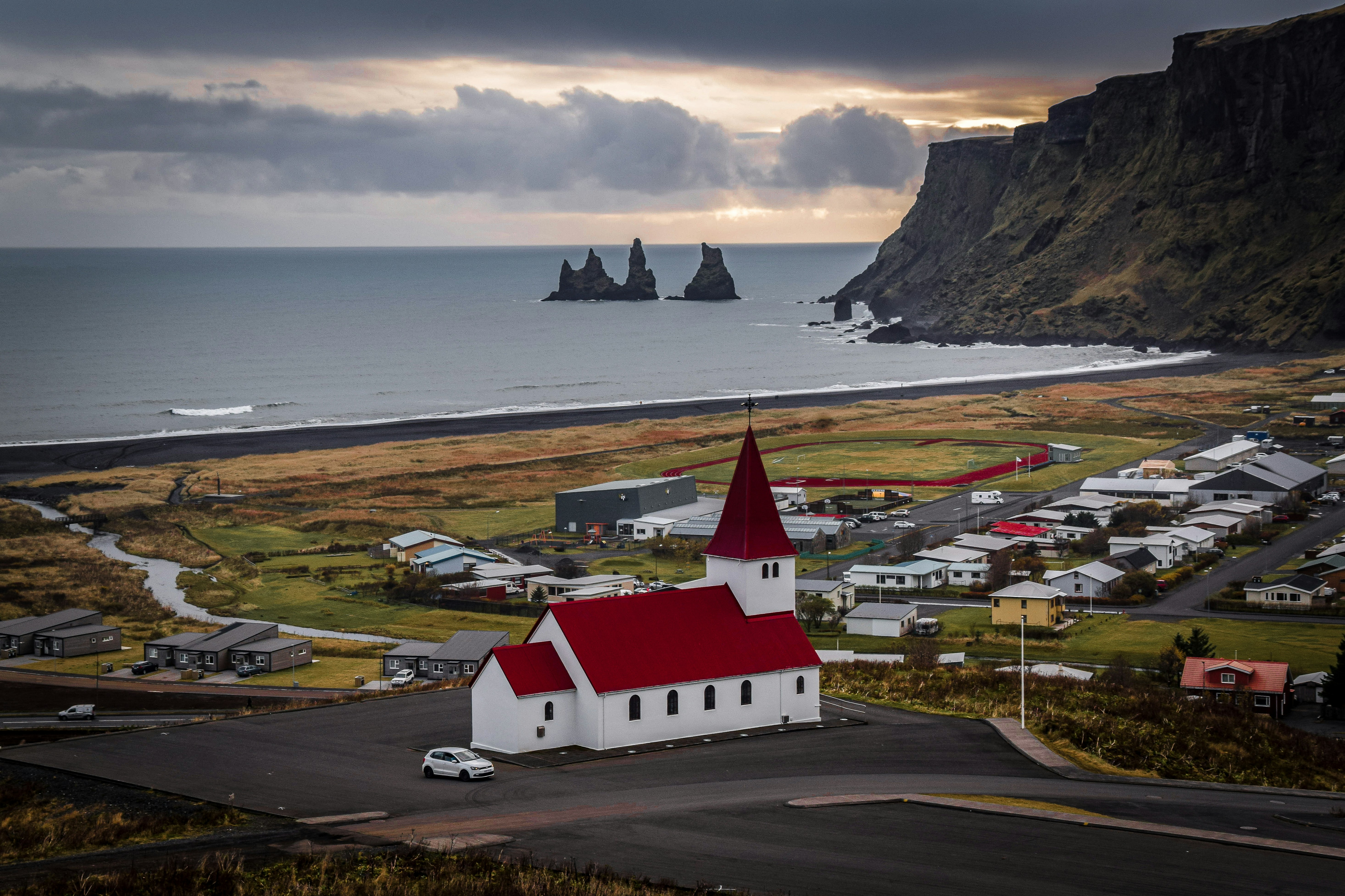 Red-roofed Church Amid Coastal Plains under Stormy Skies