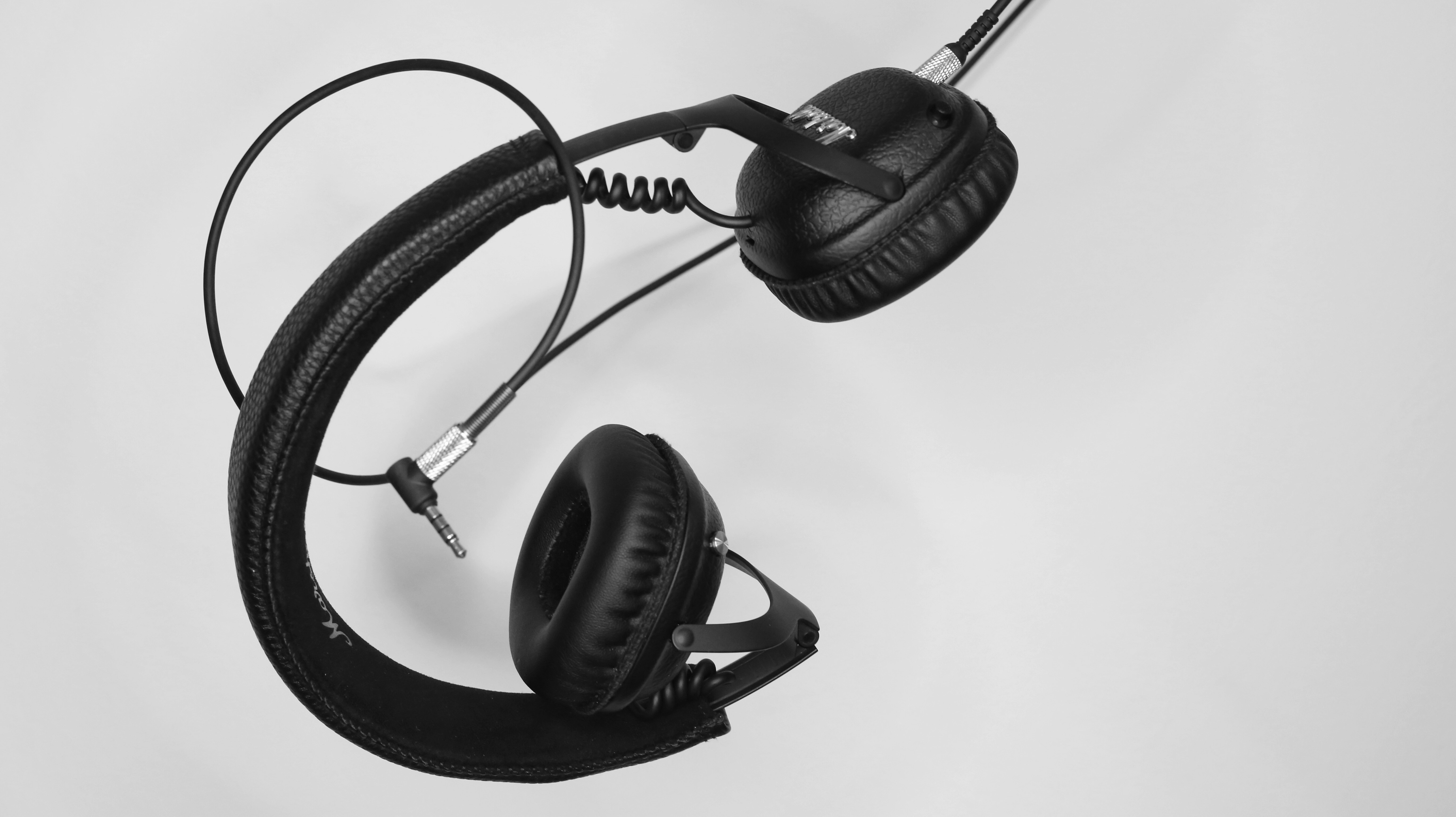 Black over-ear headphones with coiled cord on a light gray background.