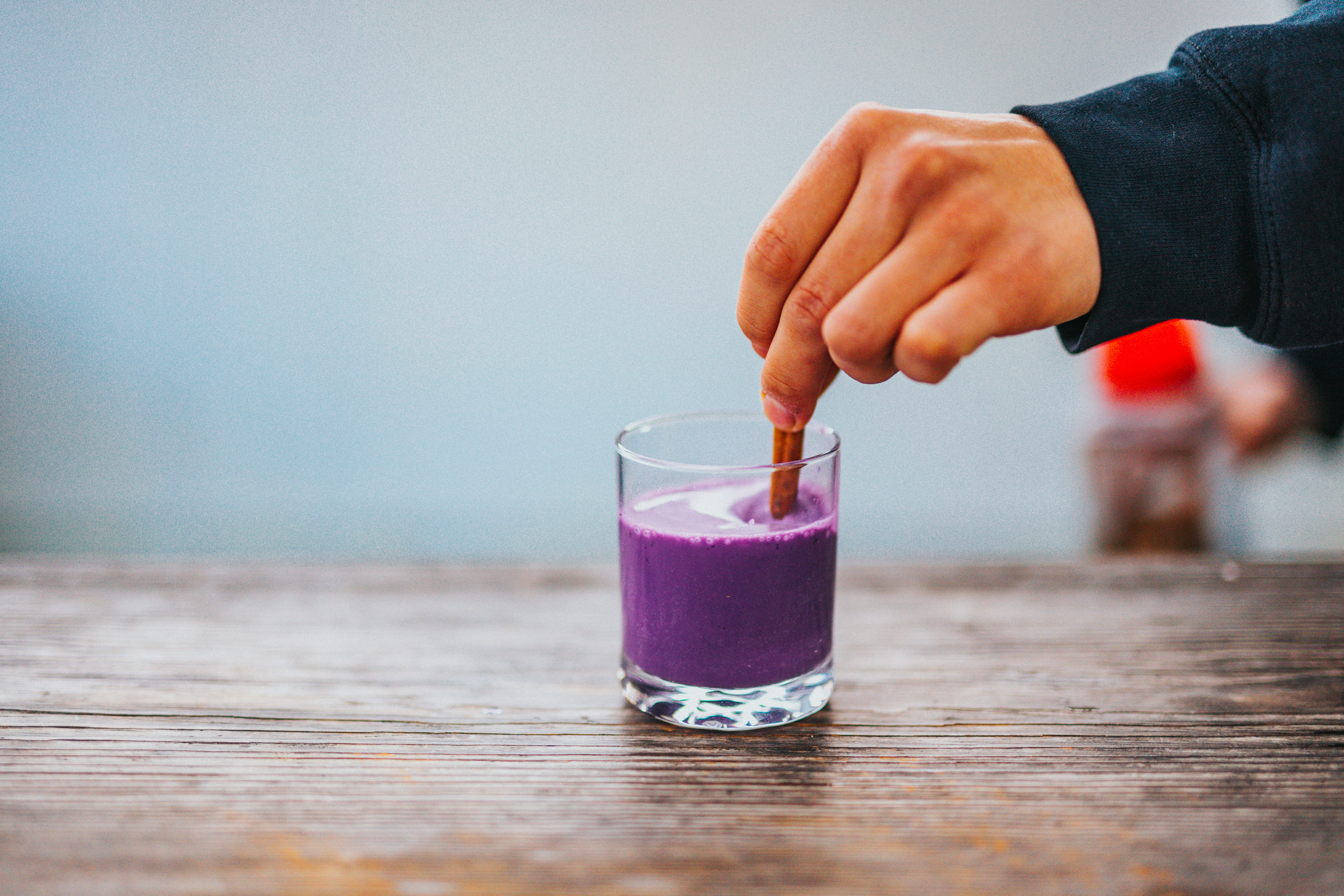 Purple Potion on a Weathered Bar: A Hand Stirs a Midnight Smoothie