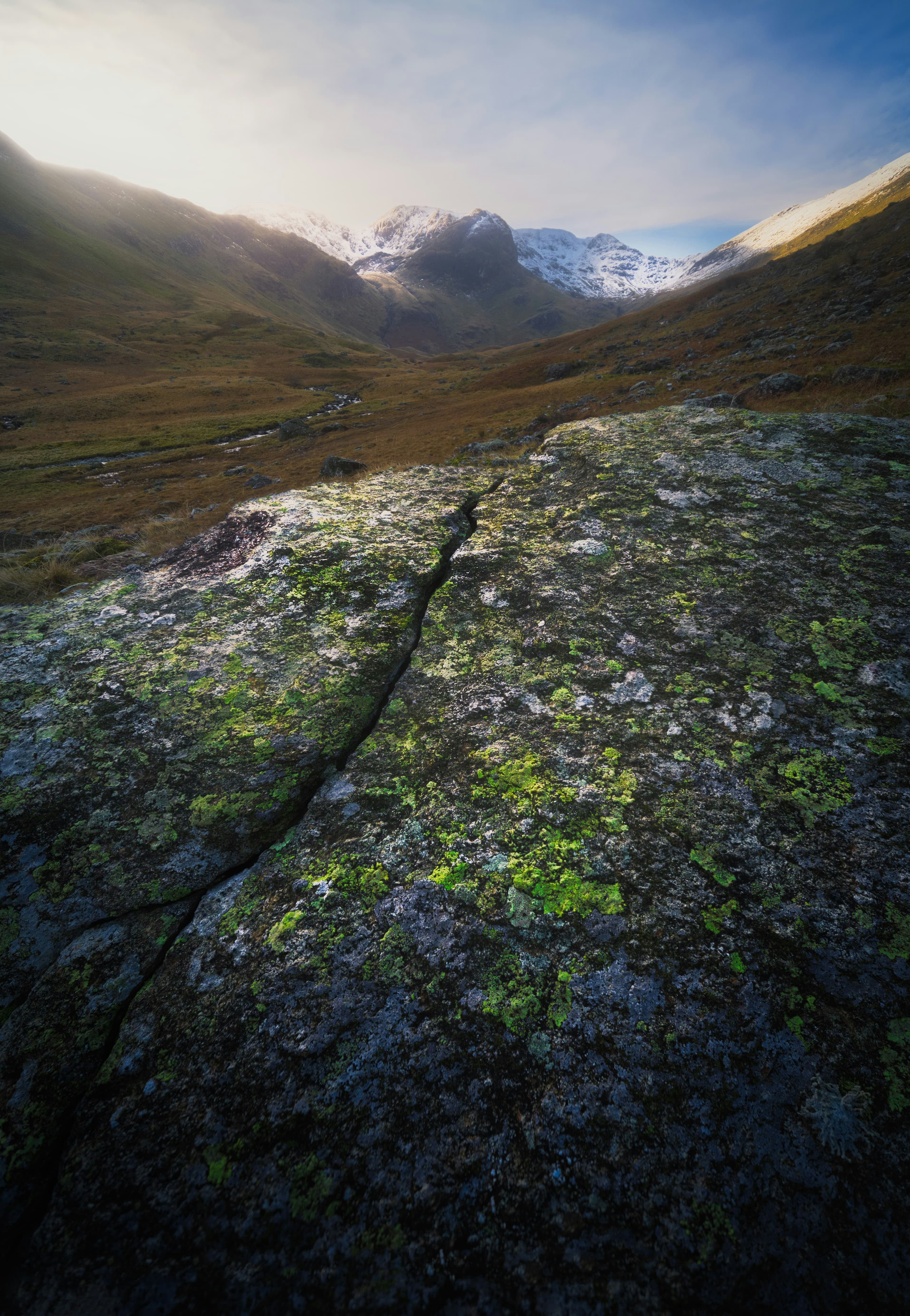 Lichen-strewn Ridge Beneath Snow-veiled Peaks at Dusk