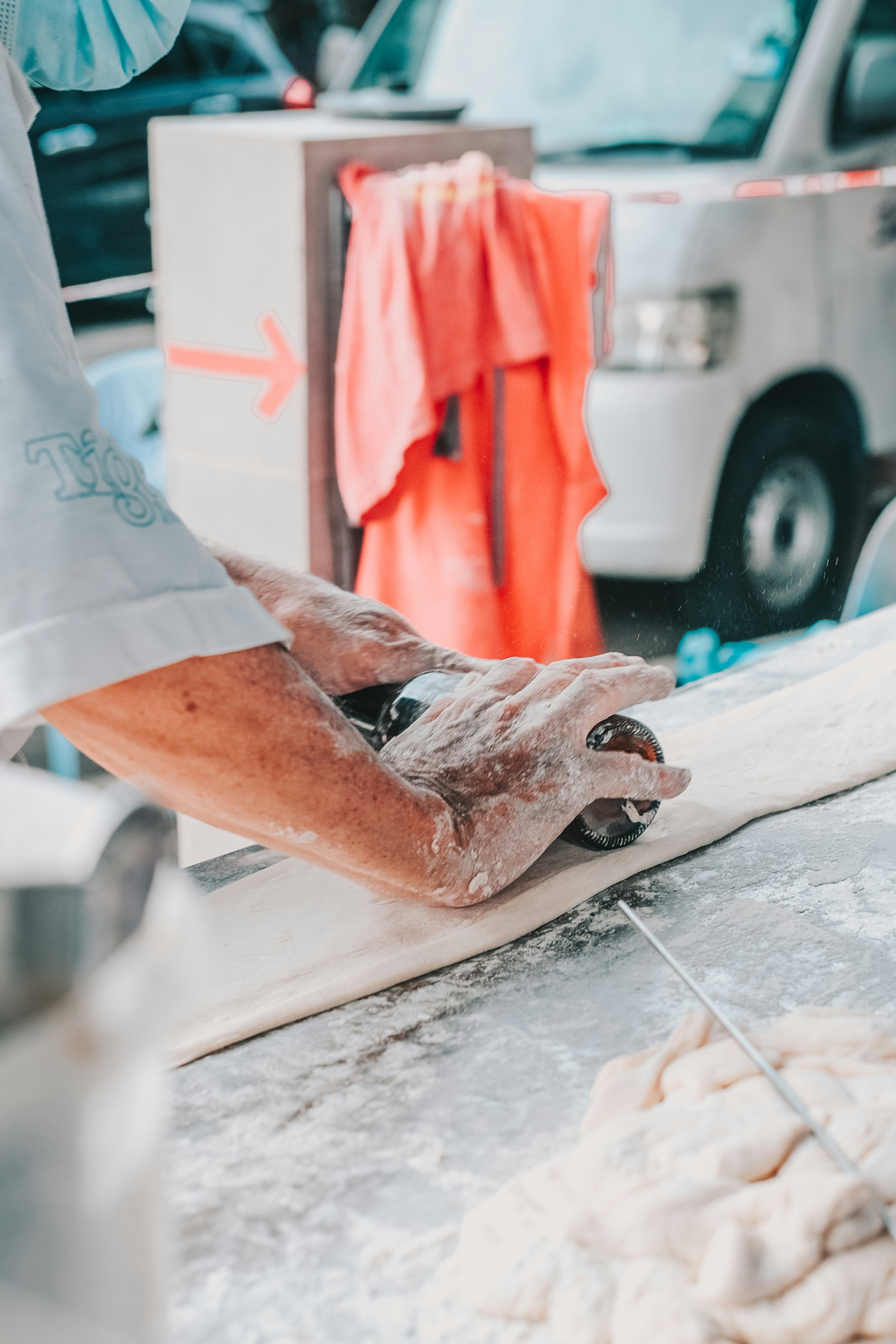 Aged uncle rolling dough with a bottle in a street market in Malaysia.