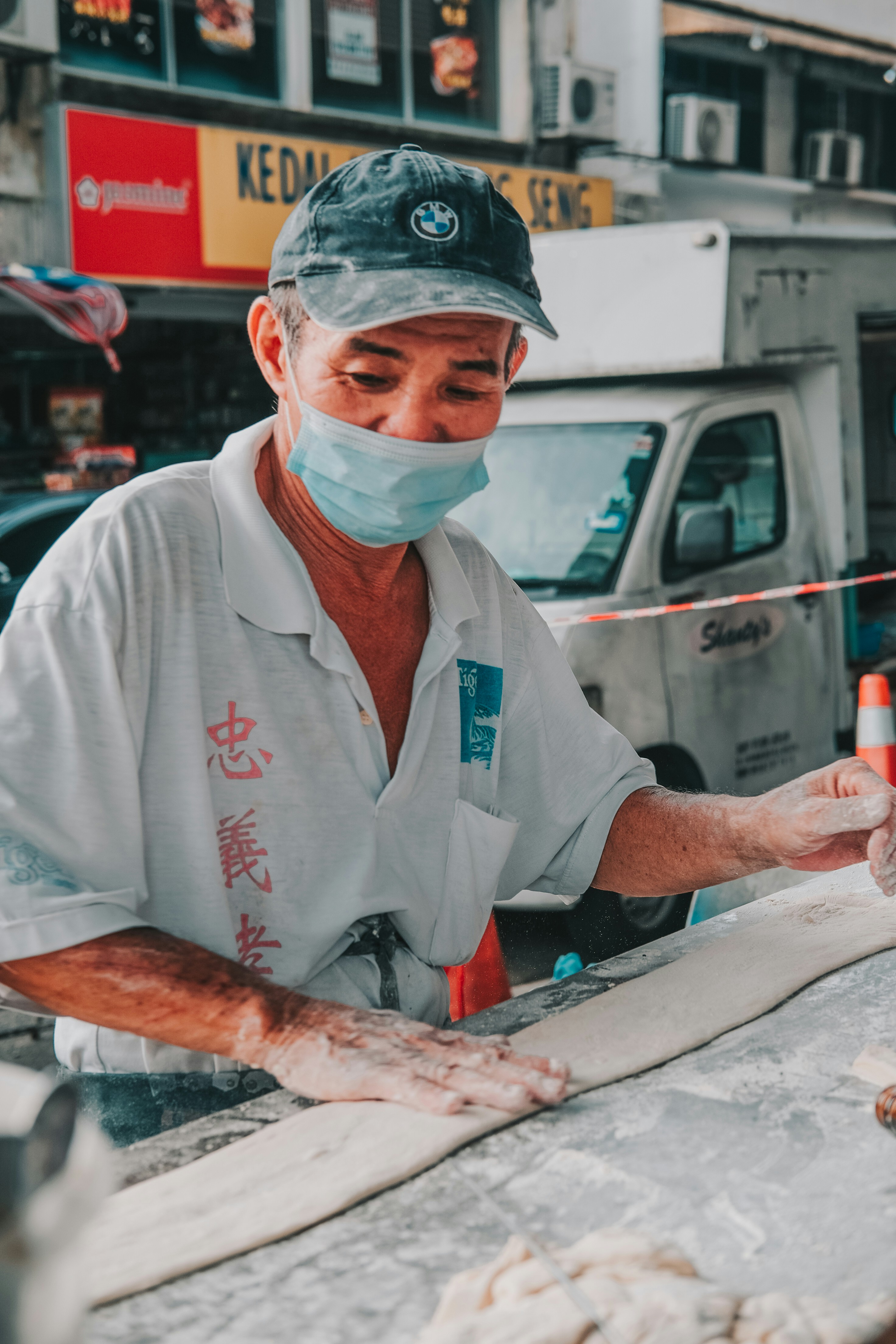 Aged uncle rolling dough in a street market in Malaysia.