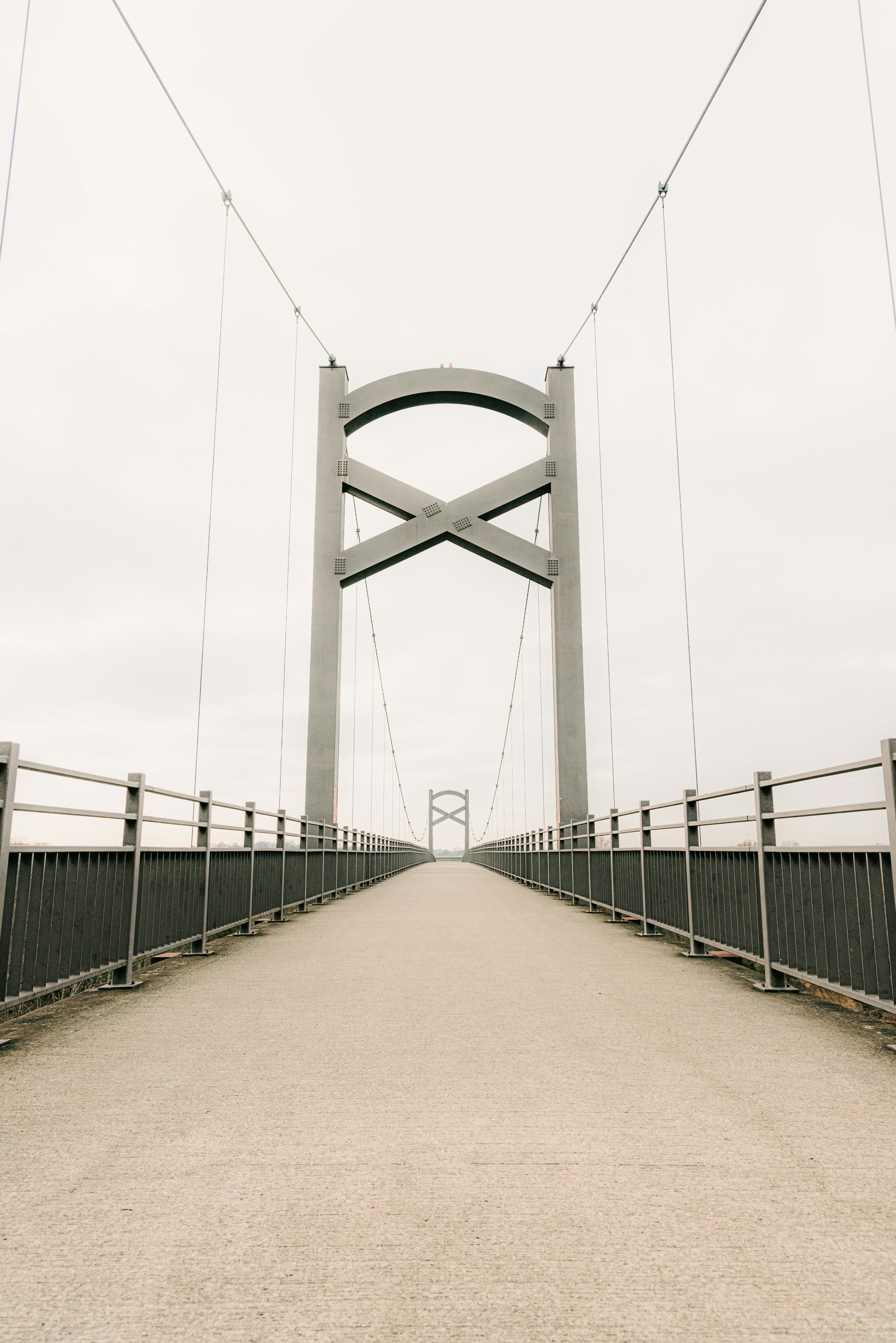 Vanishing Span: A Pedestrian Bridge Reaching Toward a Distant Arch