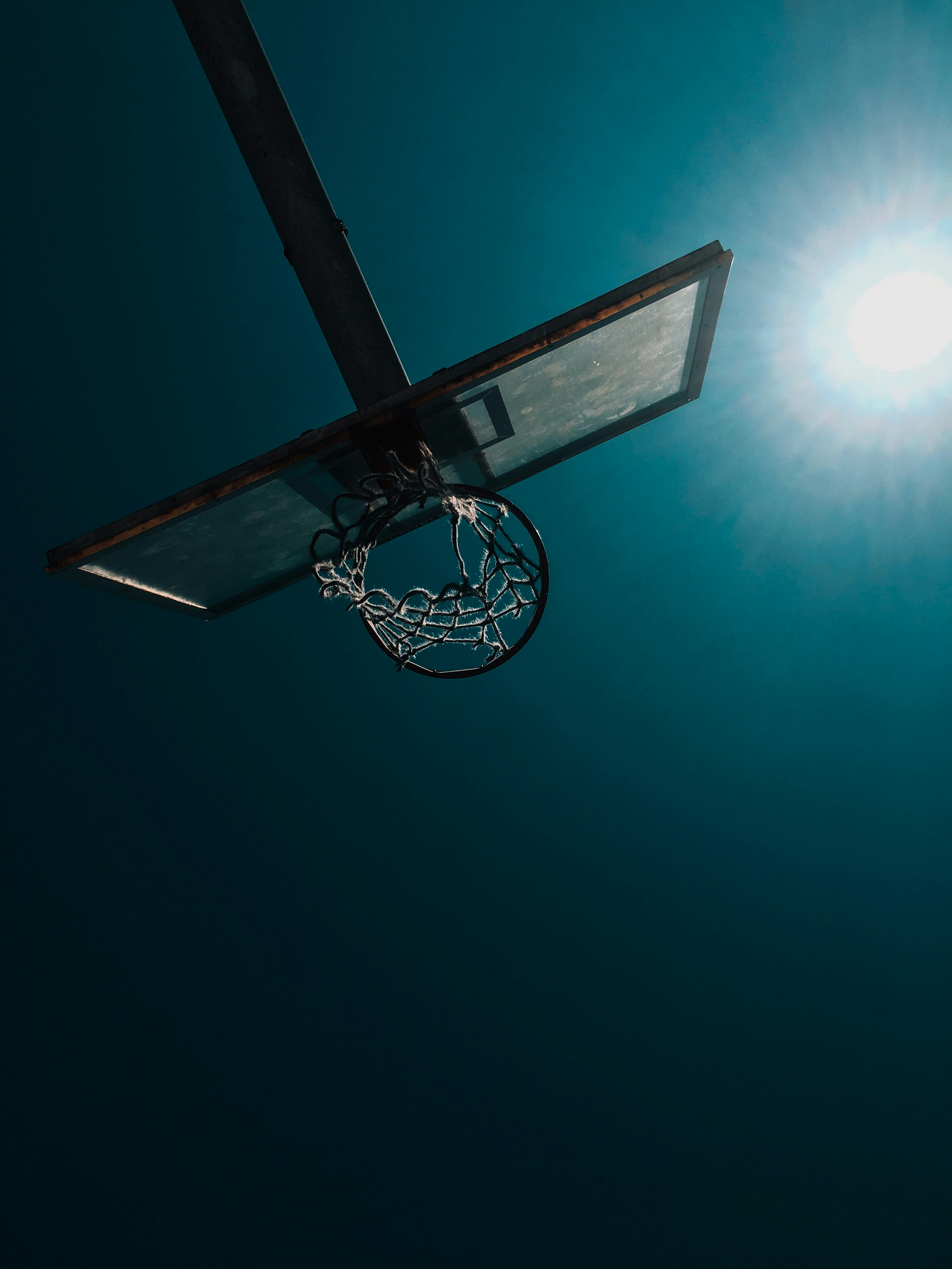 Sunlit Tilt: A Low-Angle Portrait of a Basketball Hoop