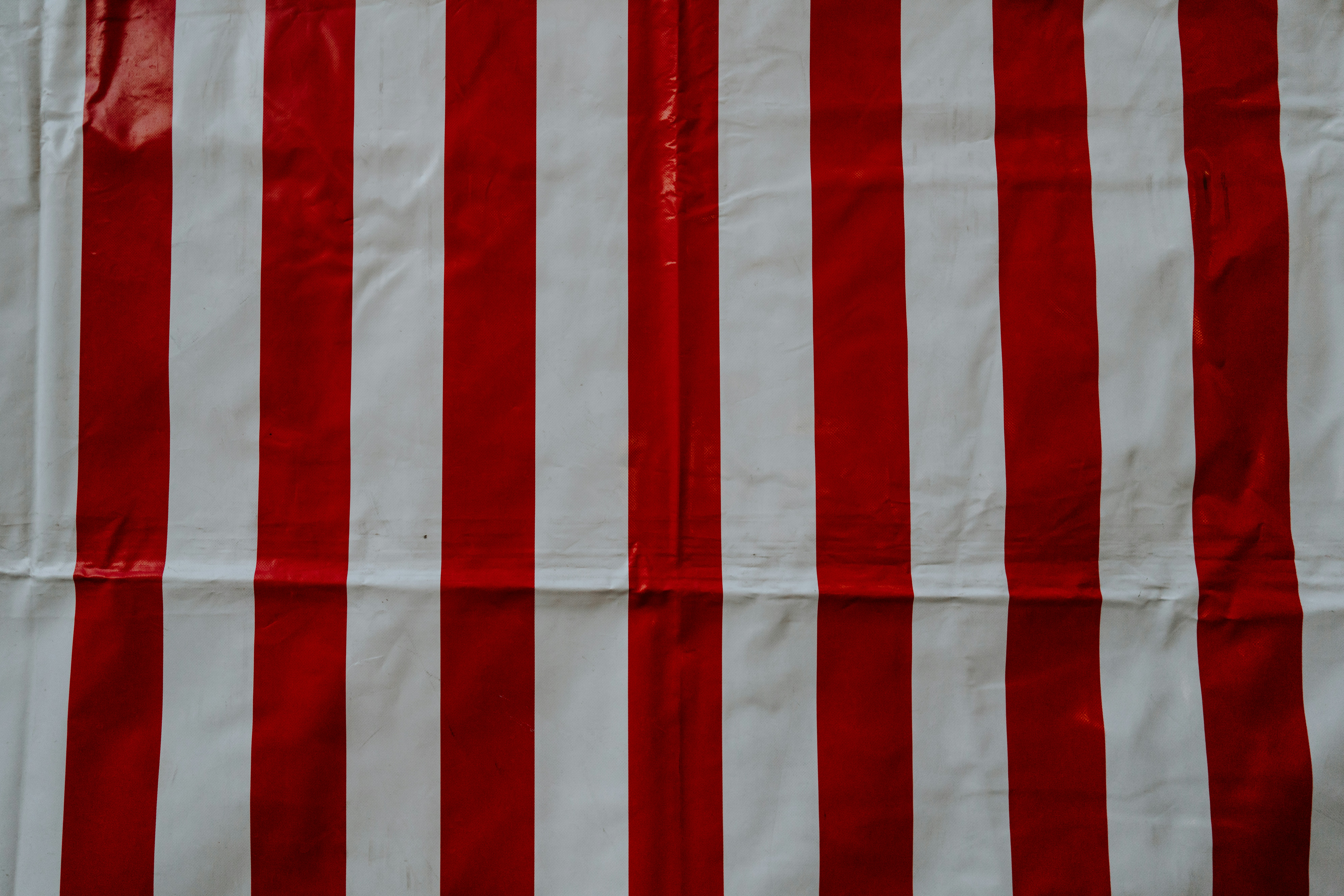 Vertical red and white stripes create a bold, graphic pattern on a textured surface.