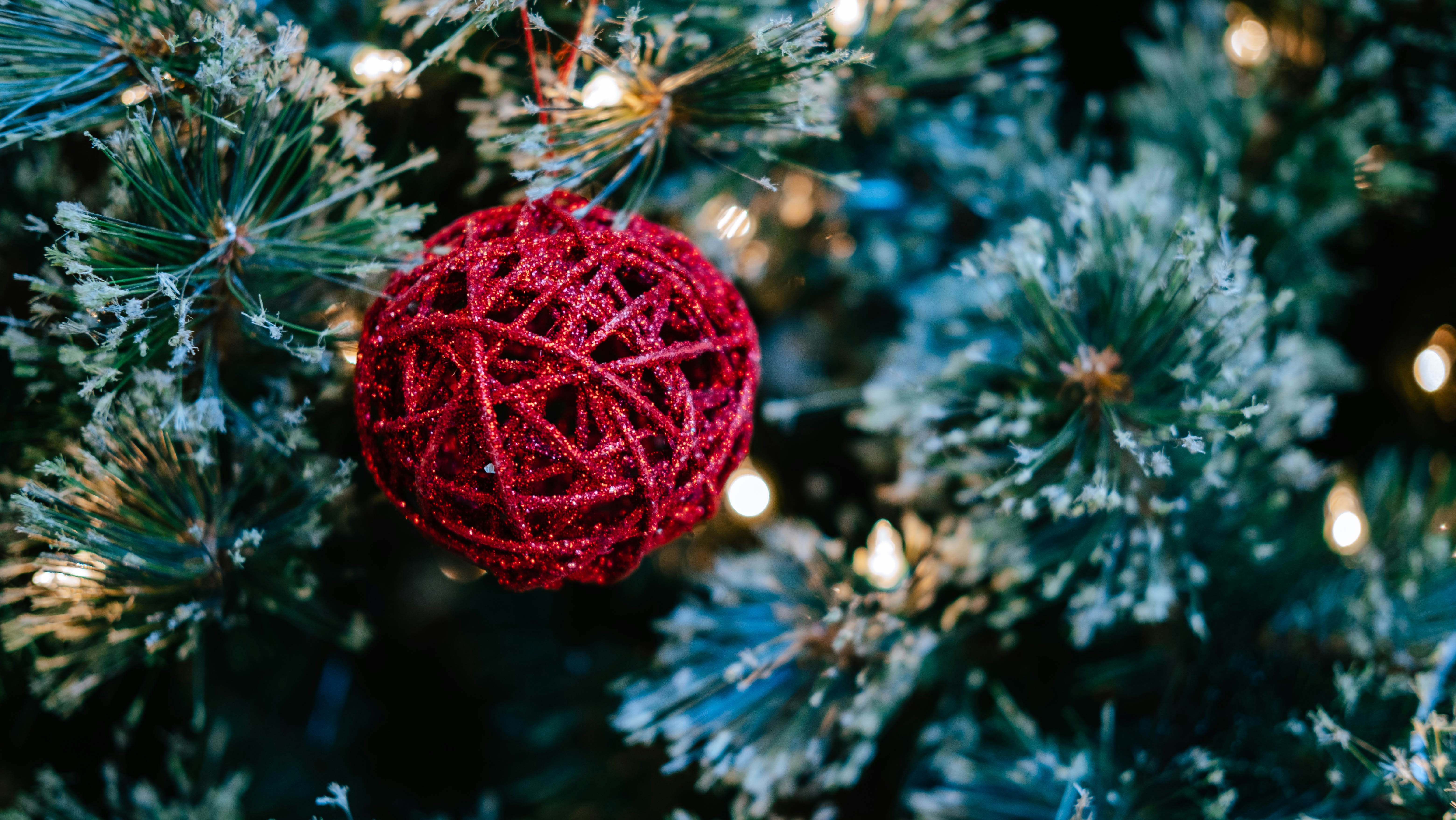Crimson Lattice Ornament on Frosted Pine Beneath Gentle Holiday Glow