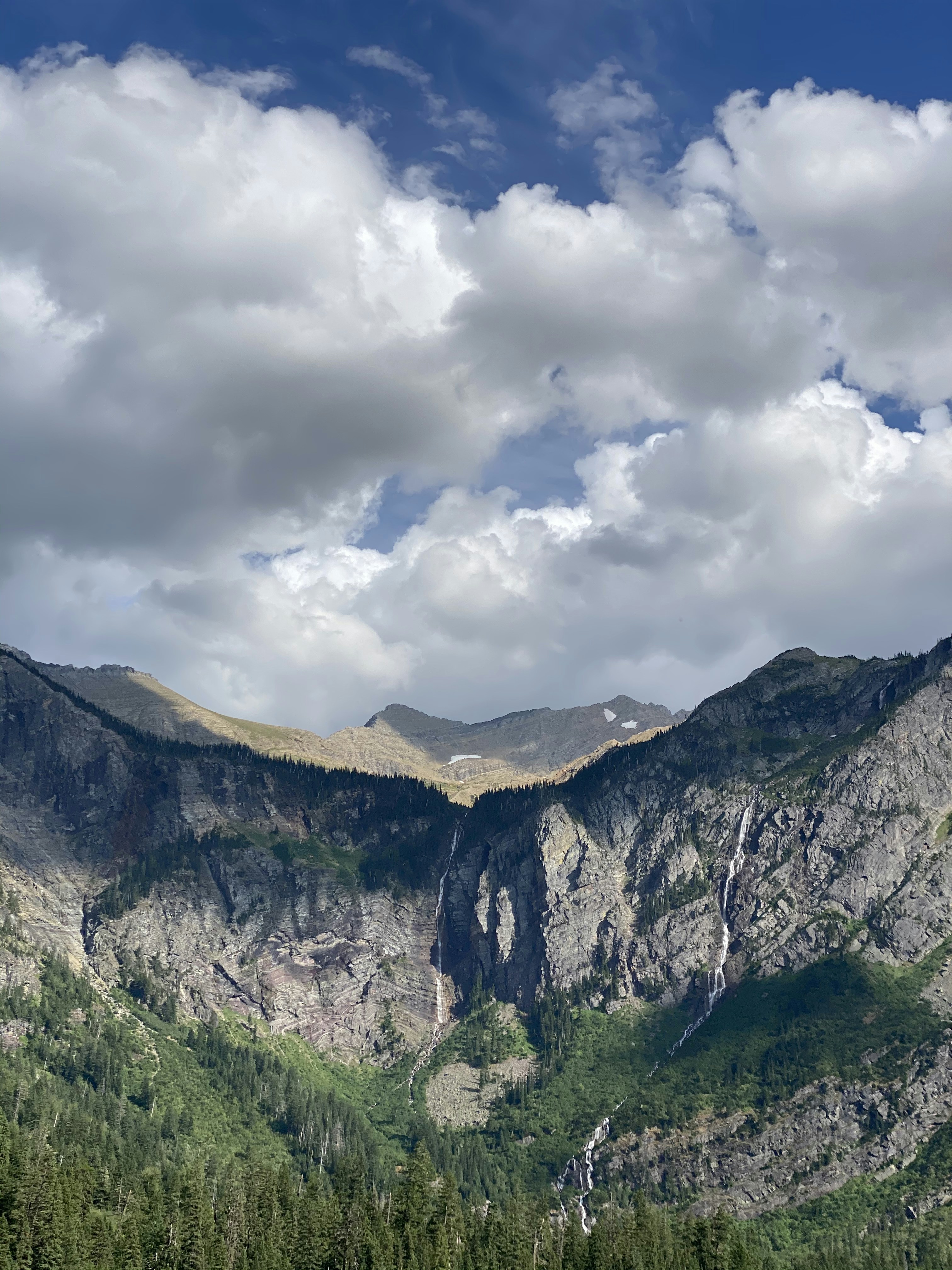 Majestic mountain range with cascading waterfalls and a dramatic sky, showcasing the beauty of nature's rugged terrain.