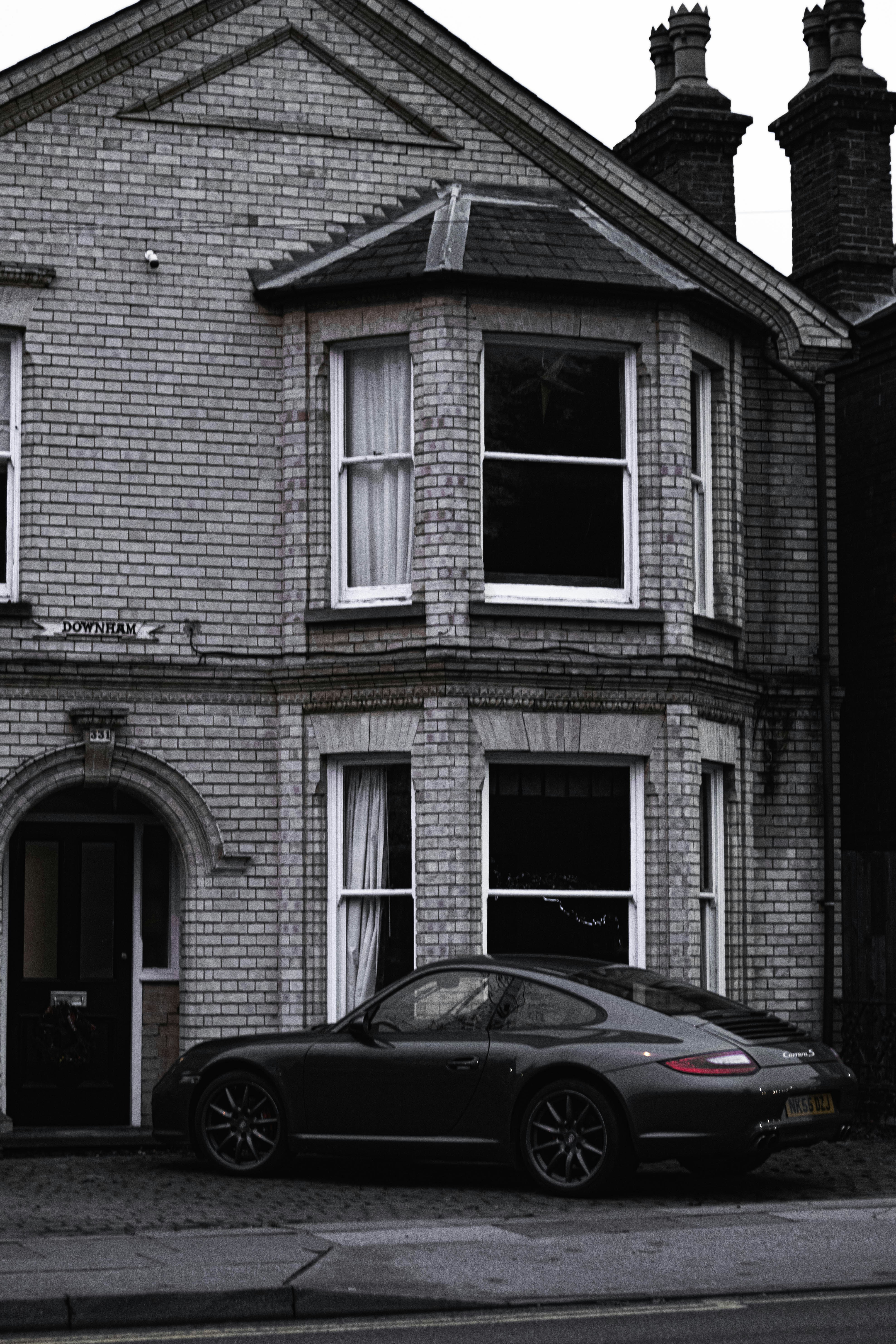 Monochrome Quiet: A Porsche Resting by a Victorian Brick Facade
