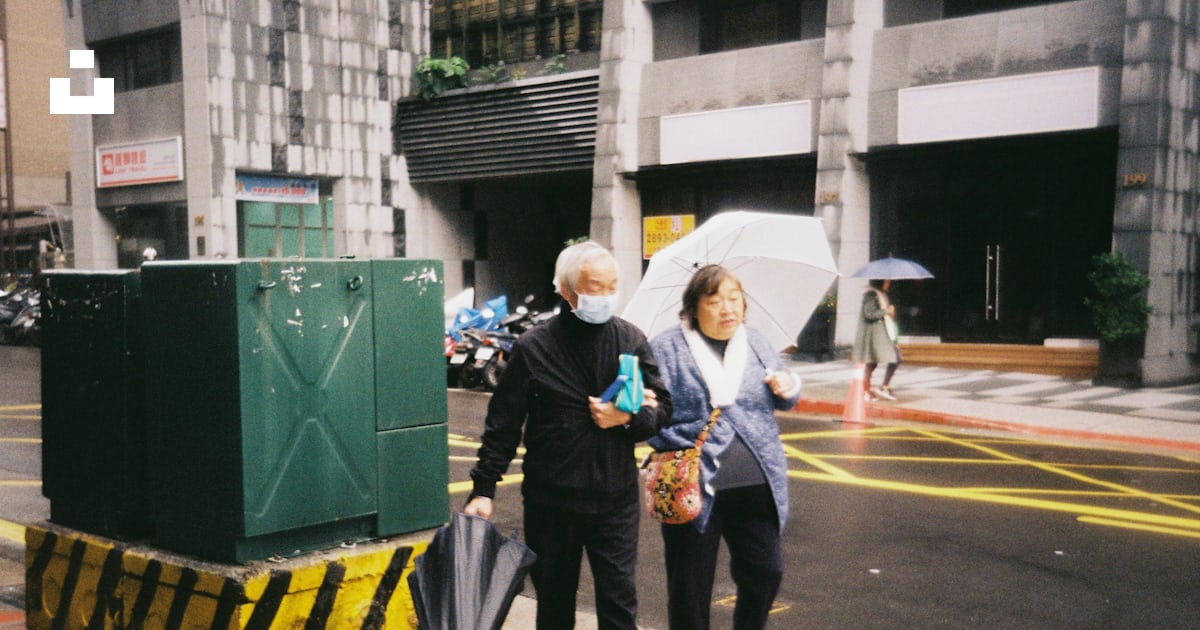 黄色と黒のジャケットを着た女性の横に立つ青いジャケットと黒いズボンの男性の写真 Unsplashの都市の無料画像