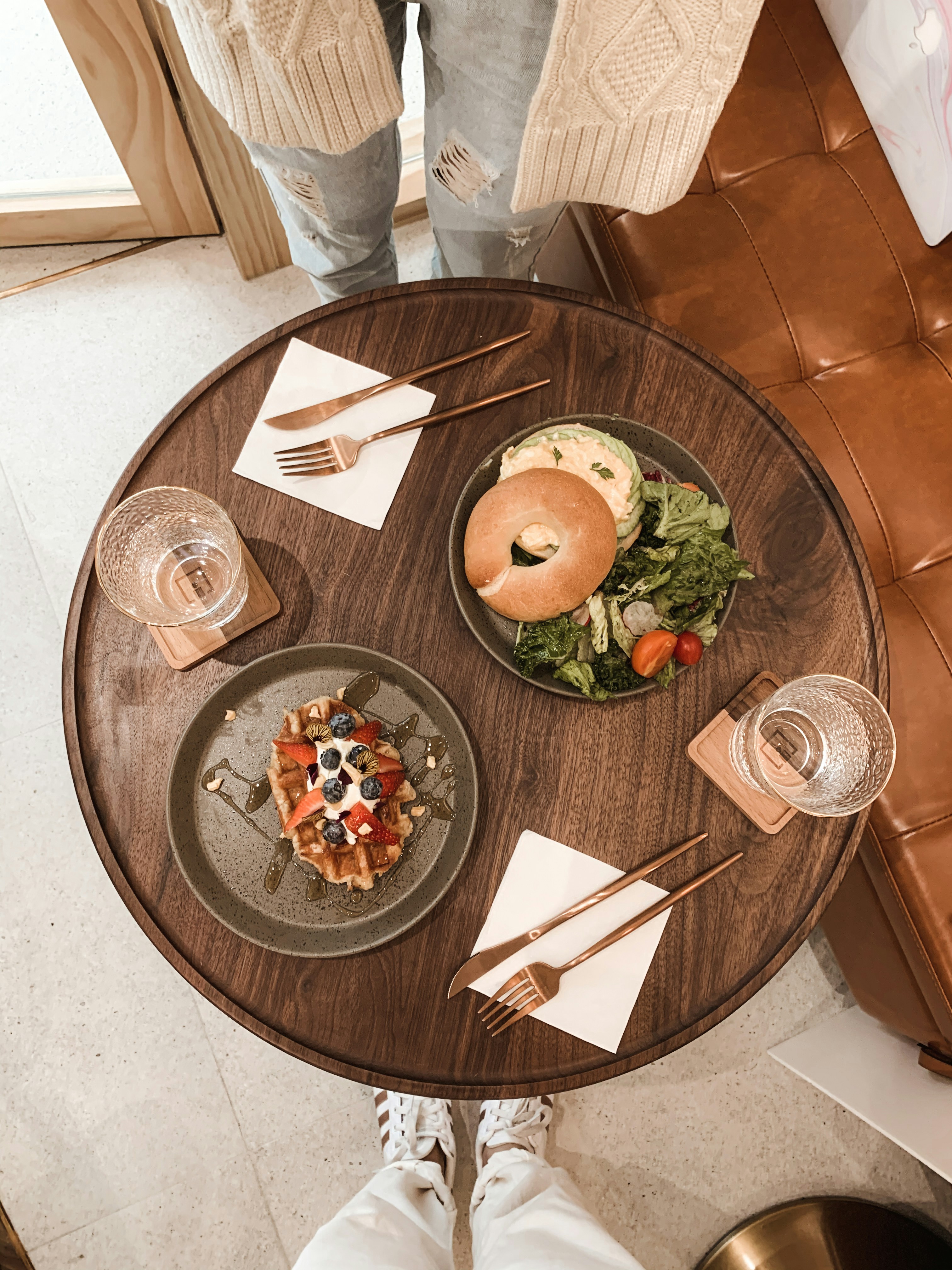 Top-Down Brunch: Bagel with Greens and Berry Waffle on a Round Table