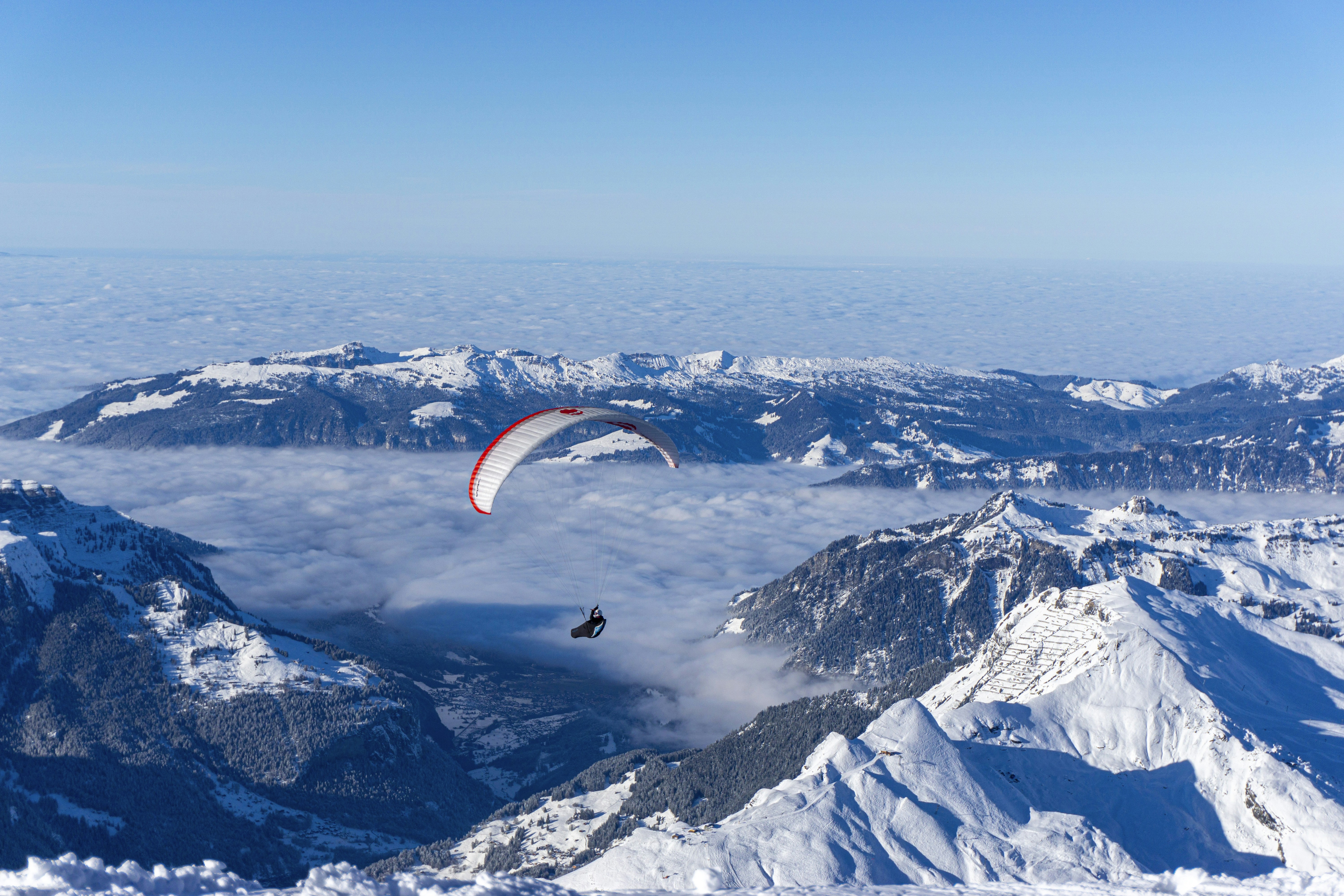 Person riding on parachute over snow covered mountain during daytime ...