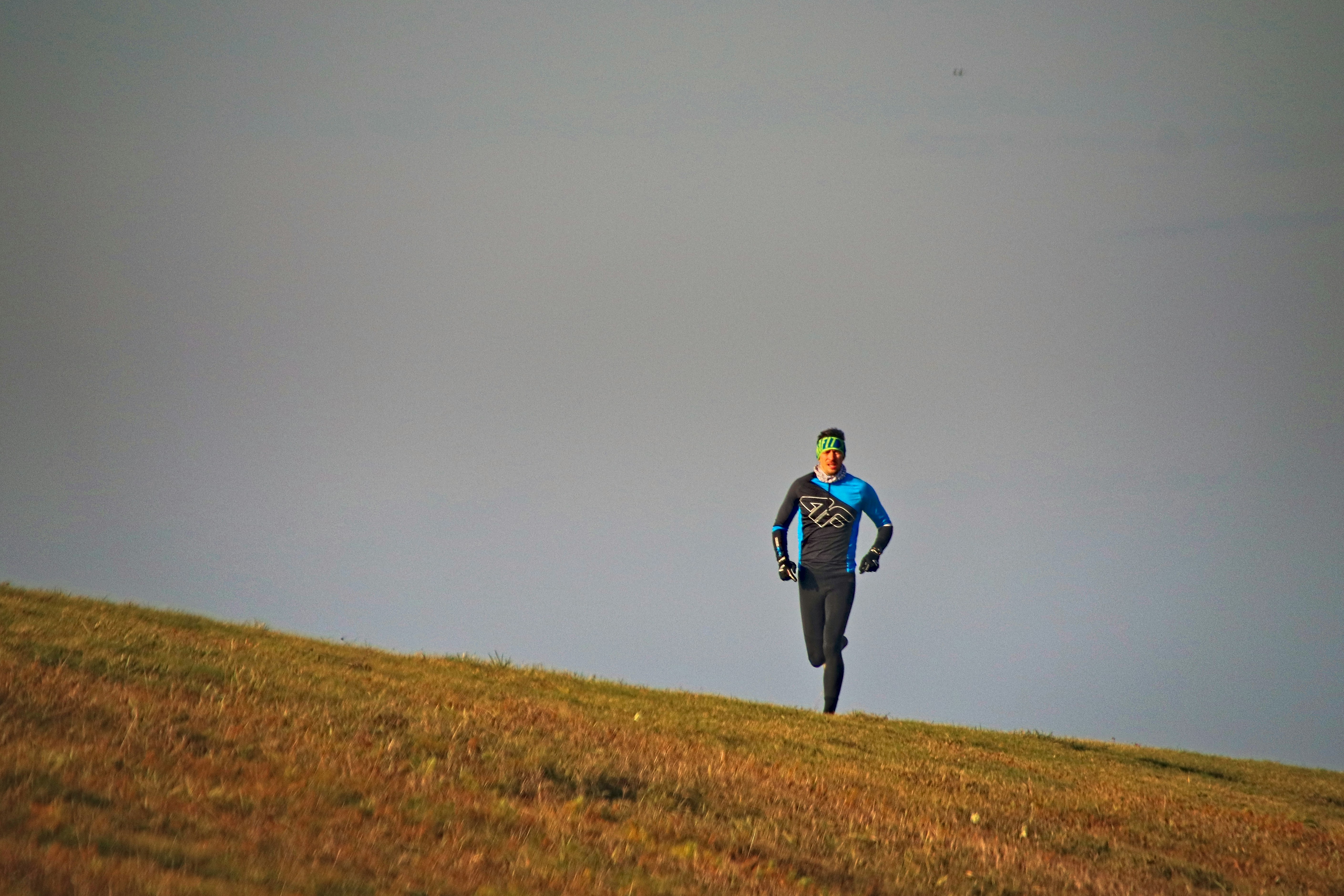 man in blue jacket walking on brown grass field