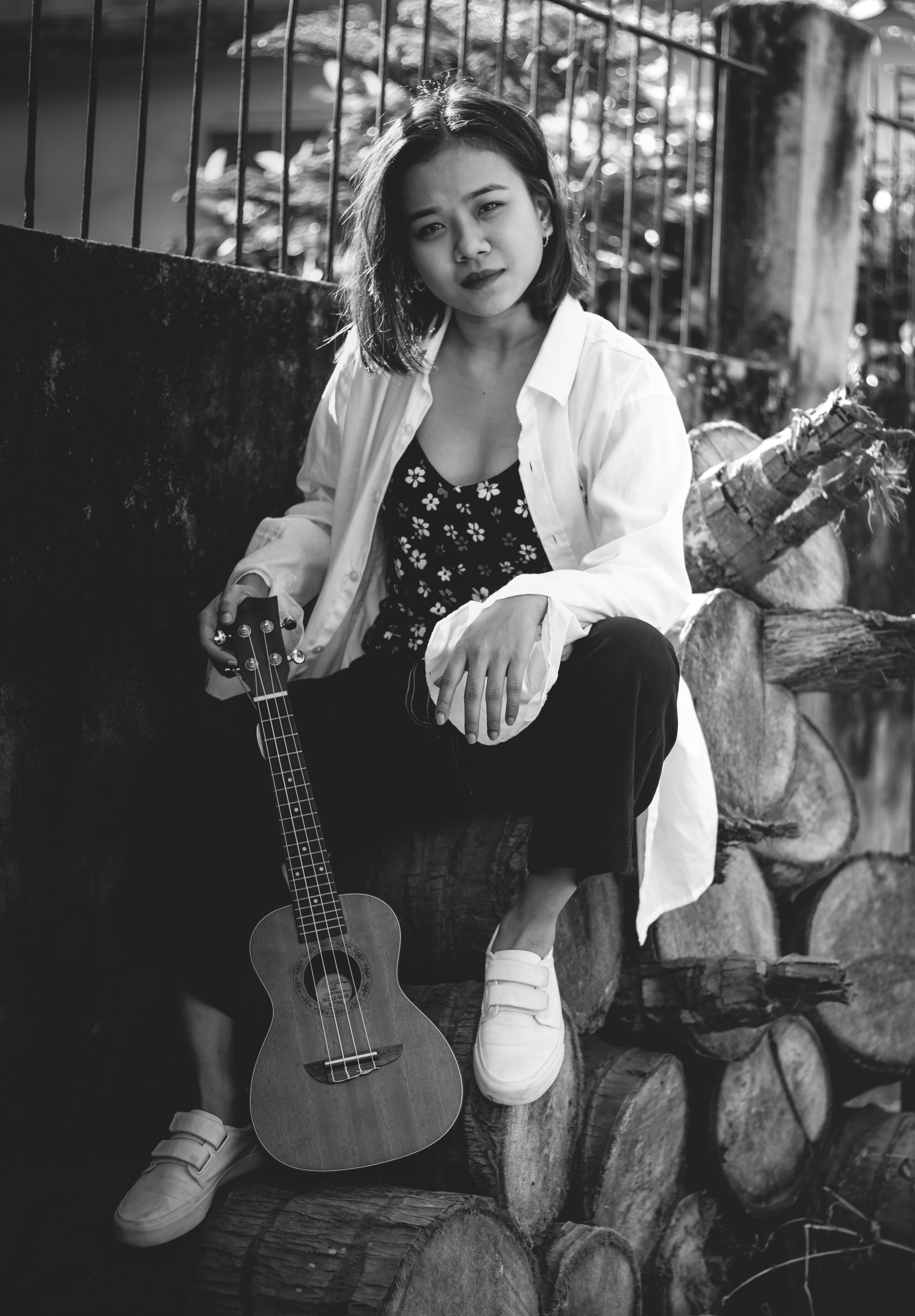 woman in white long sleeve shirt and black skirt sitting on chair playing acoustic guitar