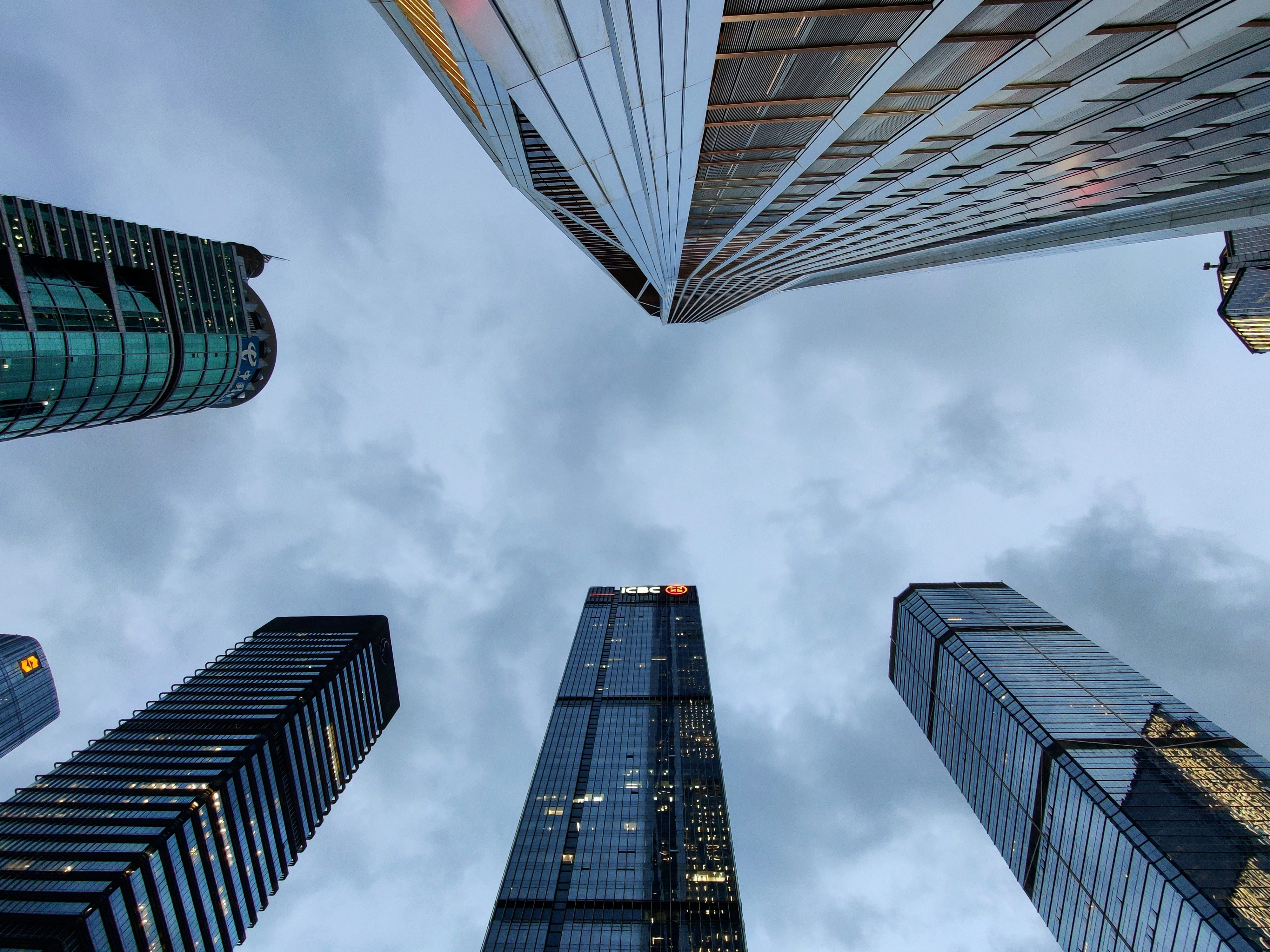 Skyscrapers reaching toward a cloudy sky from a low angle perspective.