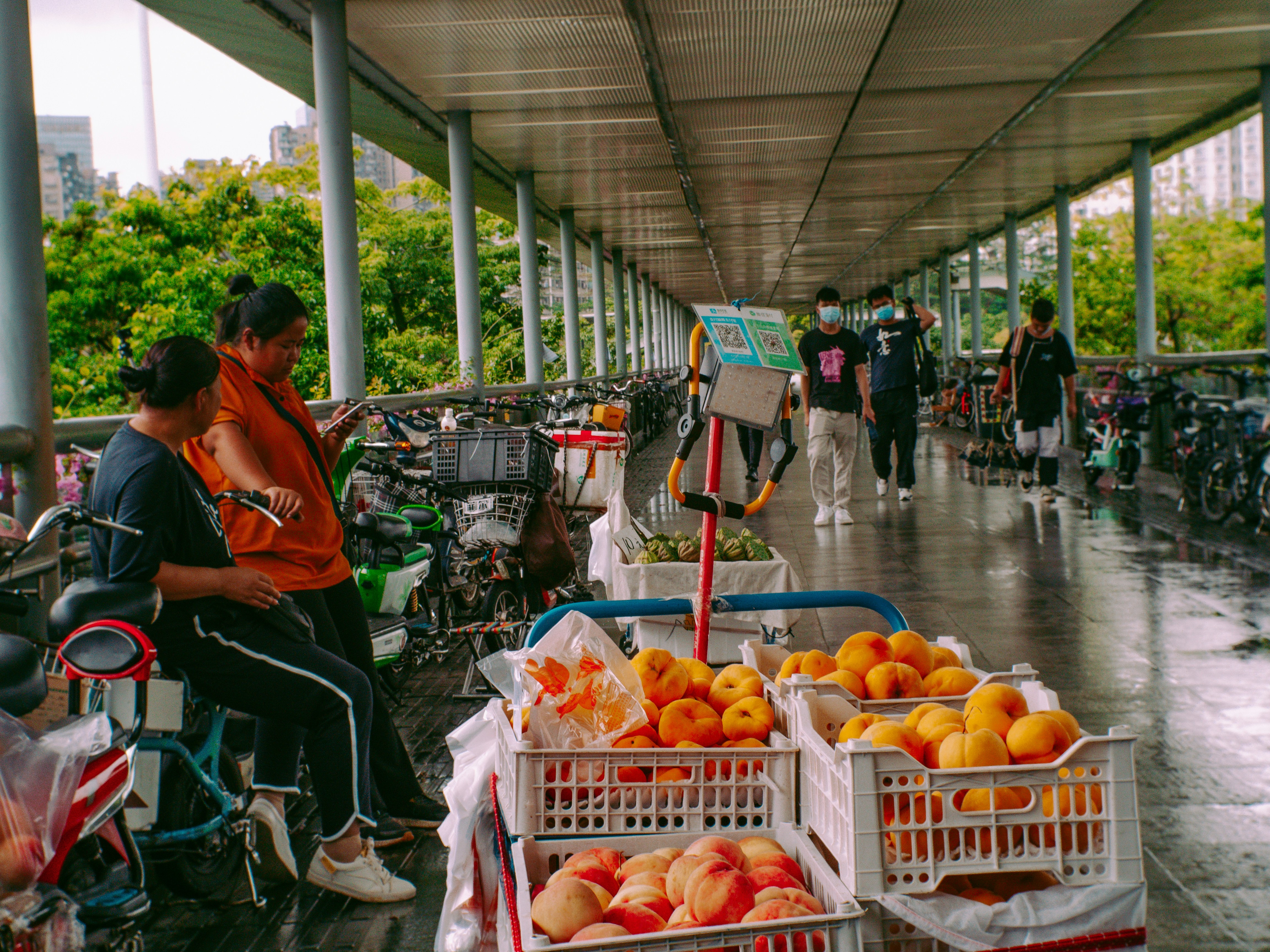 Vibrant fruit stall in a bustling market, showcasing fresh peaches and engaged shoppers amidst a lively urban backdrop.