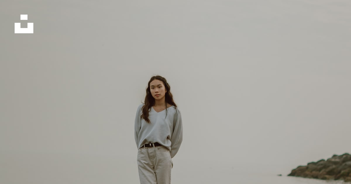 흰색 긴 소매 셔츠와 흰색 바지를 입은 여자가 온 On On 몸 근처의 갈색 바위 위에 서 있다 사진 Unsplash의