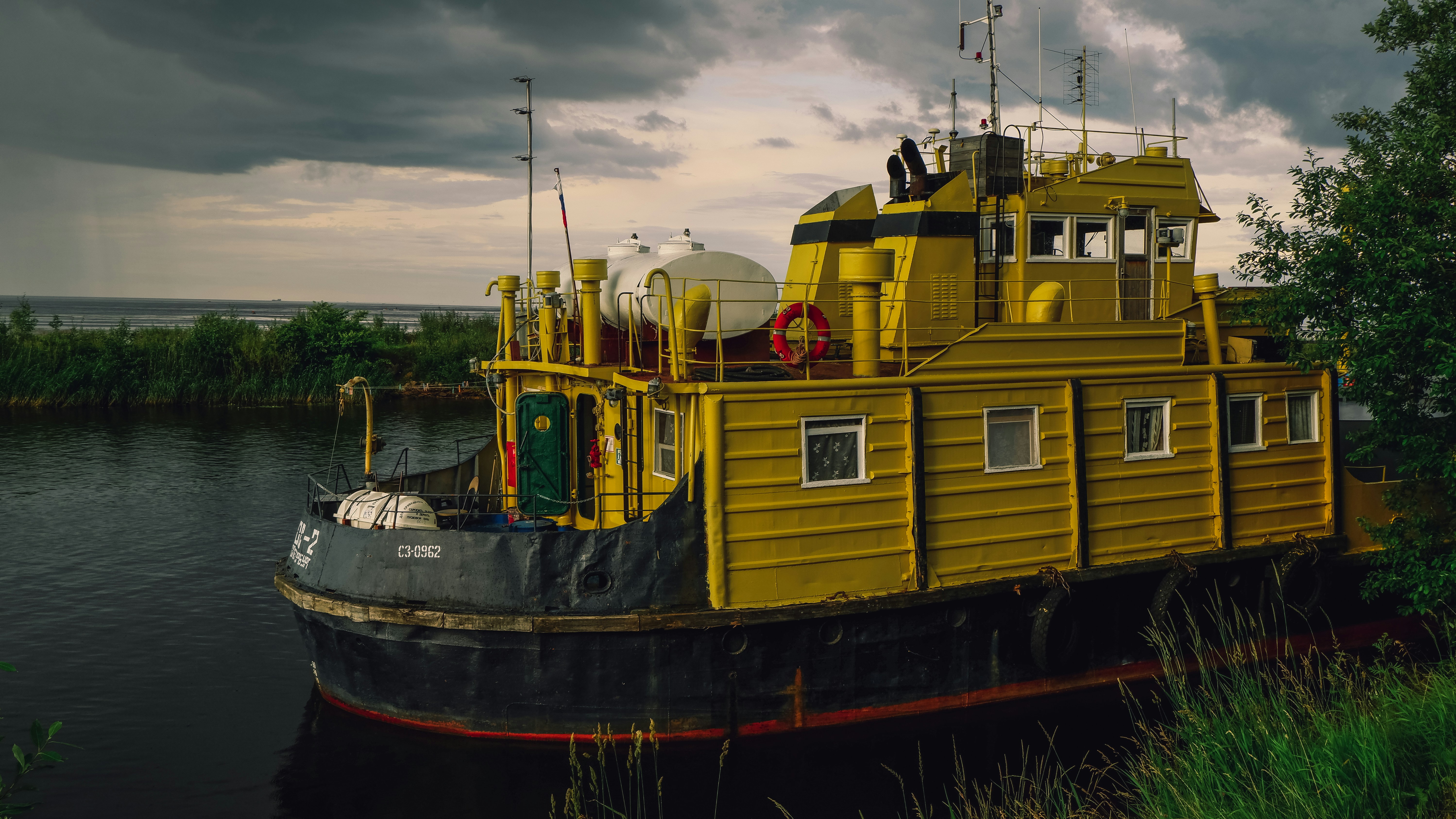 Yellow Houseboat on a Quiet River Under Brooding Clouds