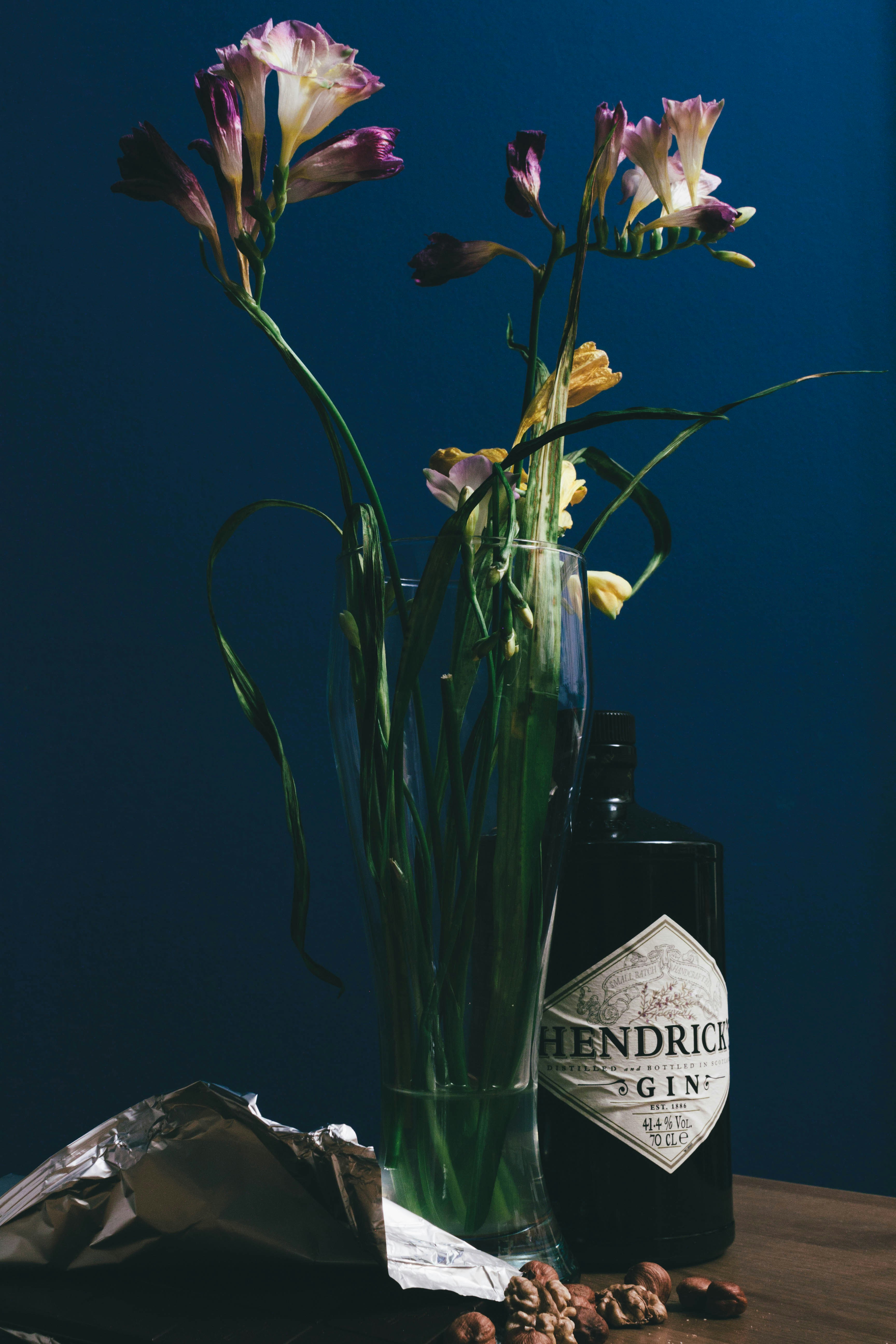 Vase of Lisianthus against a Deep Blue Backdrop with Gin Bottle