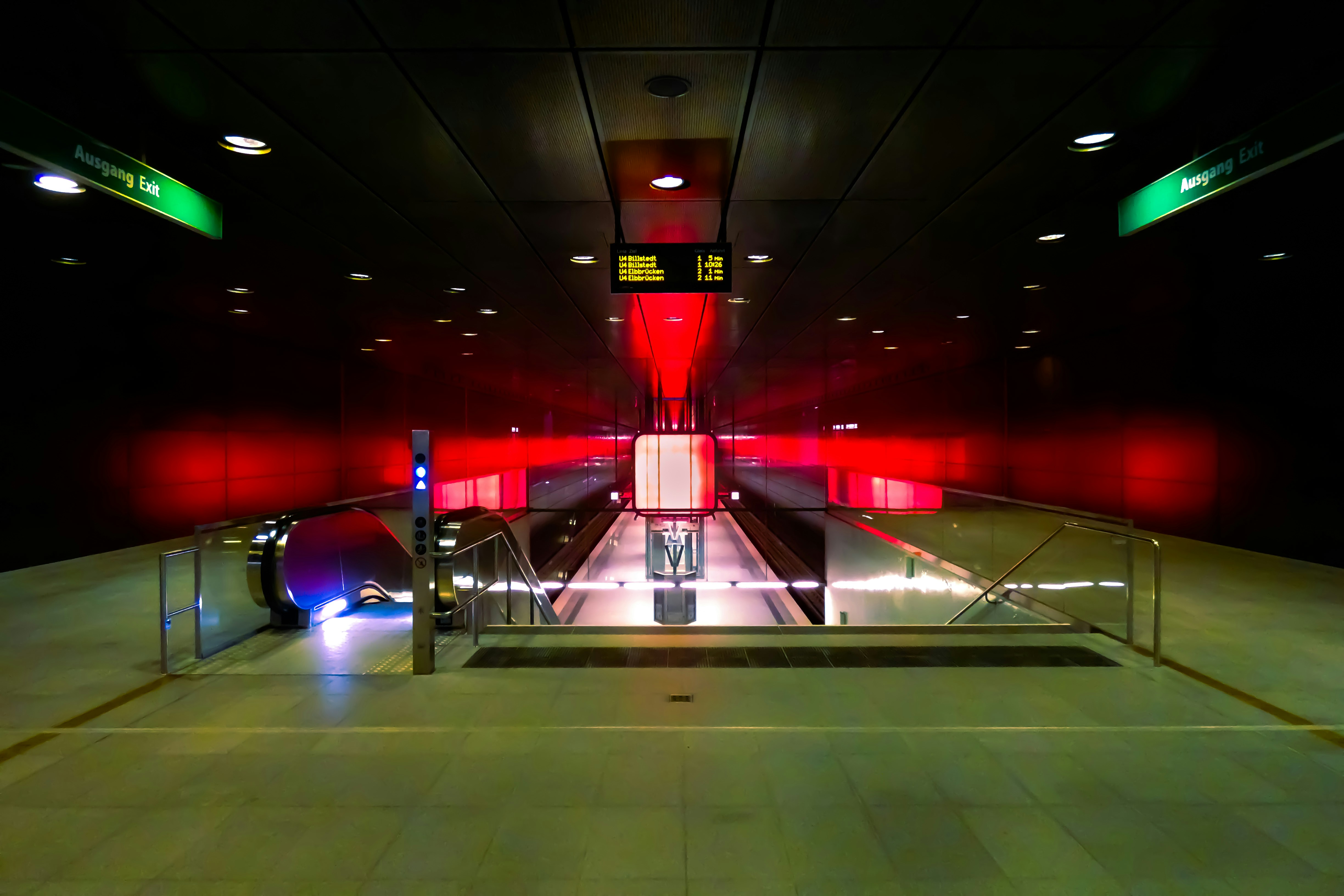 Modern subway station showcasing escalators and vibrant red lighting, creating a striking visual contrast against sleek architectural lines.