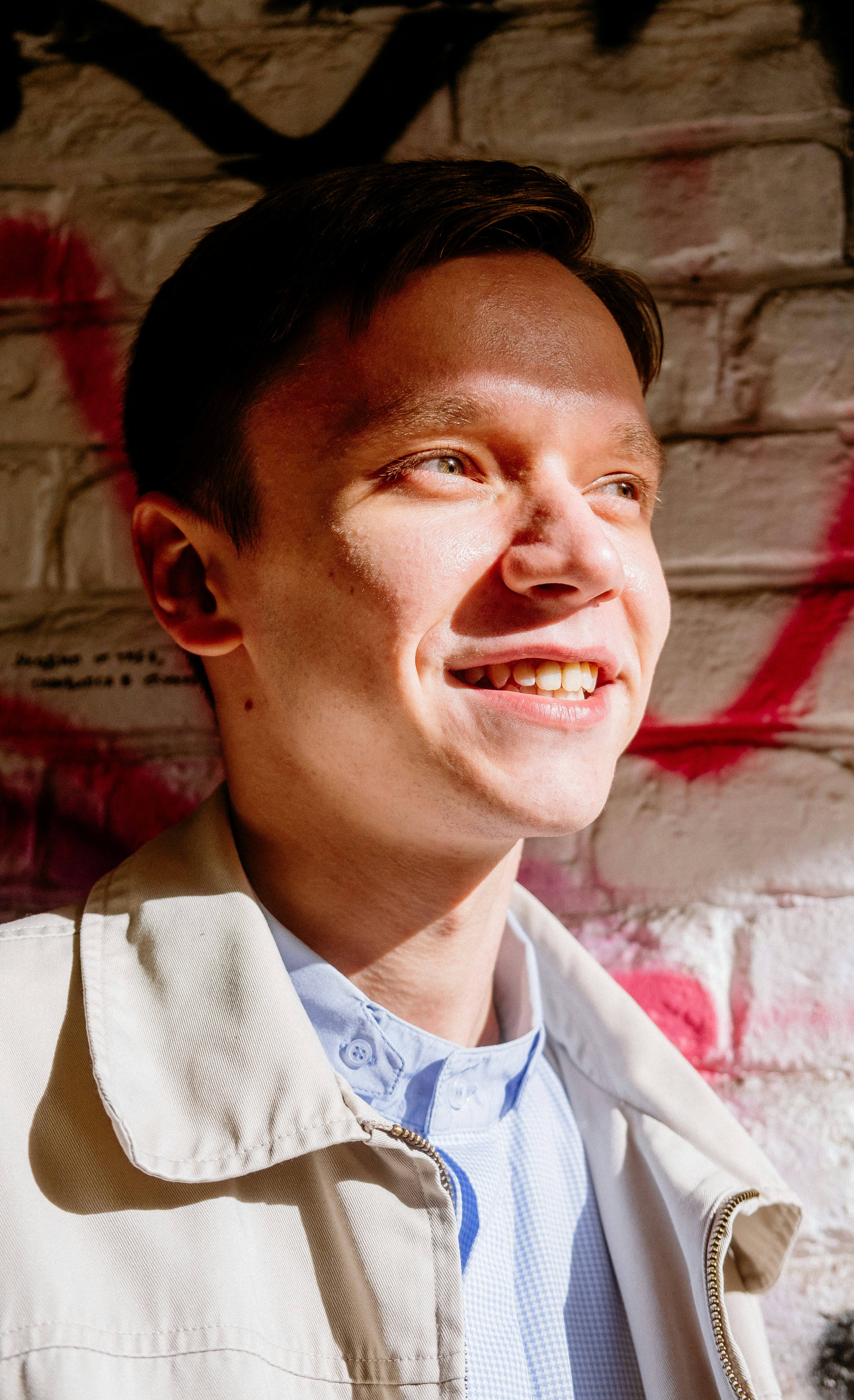 Sunlit Grin: A Portrait with Brick-Backdrop Glow