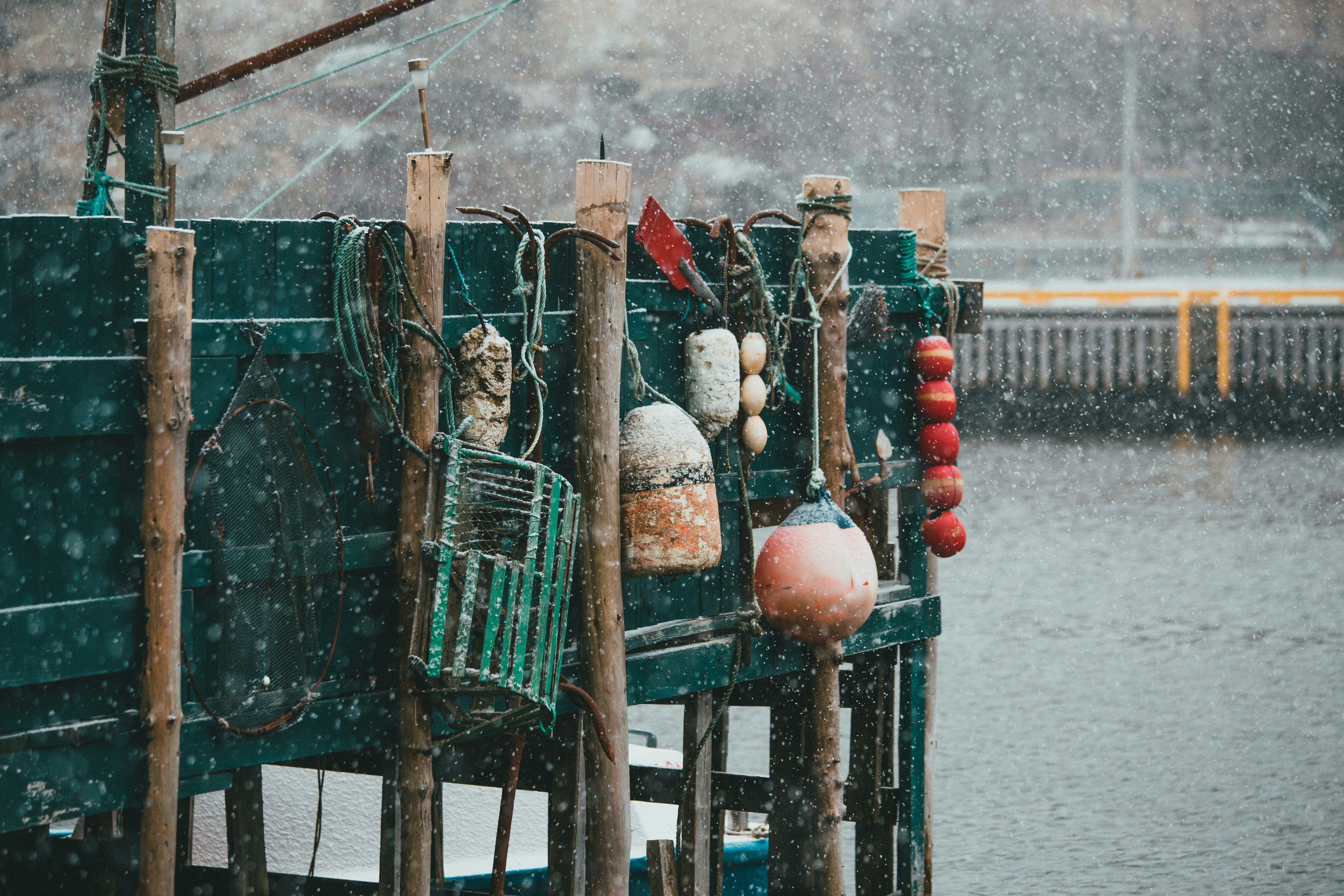 Snowfall on a Weathered Wharf: Buoys and Green Slats in Calm Harbor