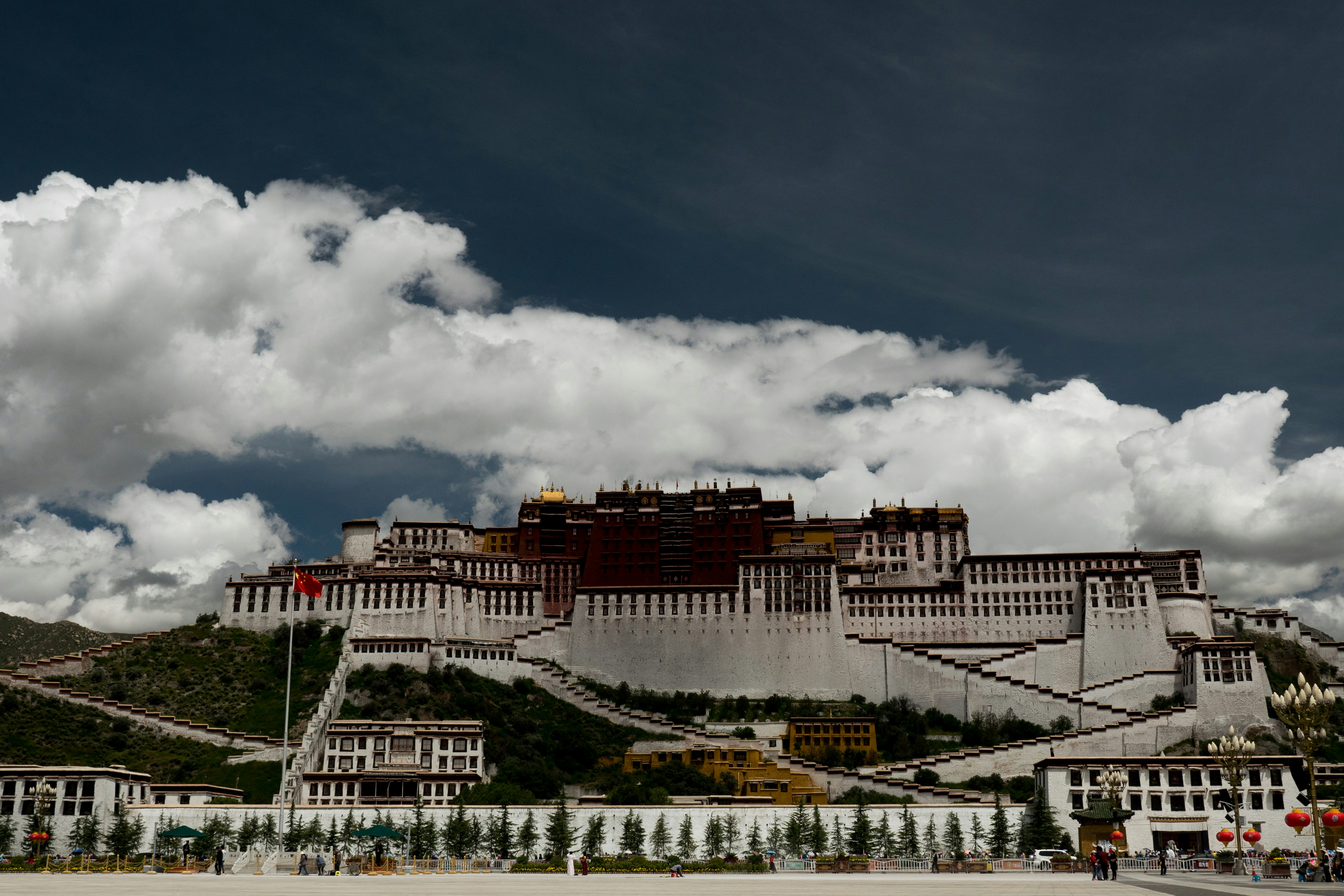 The Potala Palace stands majestically against a backdrop of dramatic clouds, showcasing its intricate architecture and historical significance.