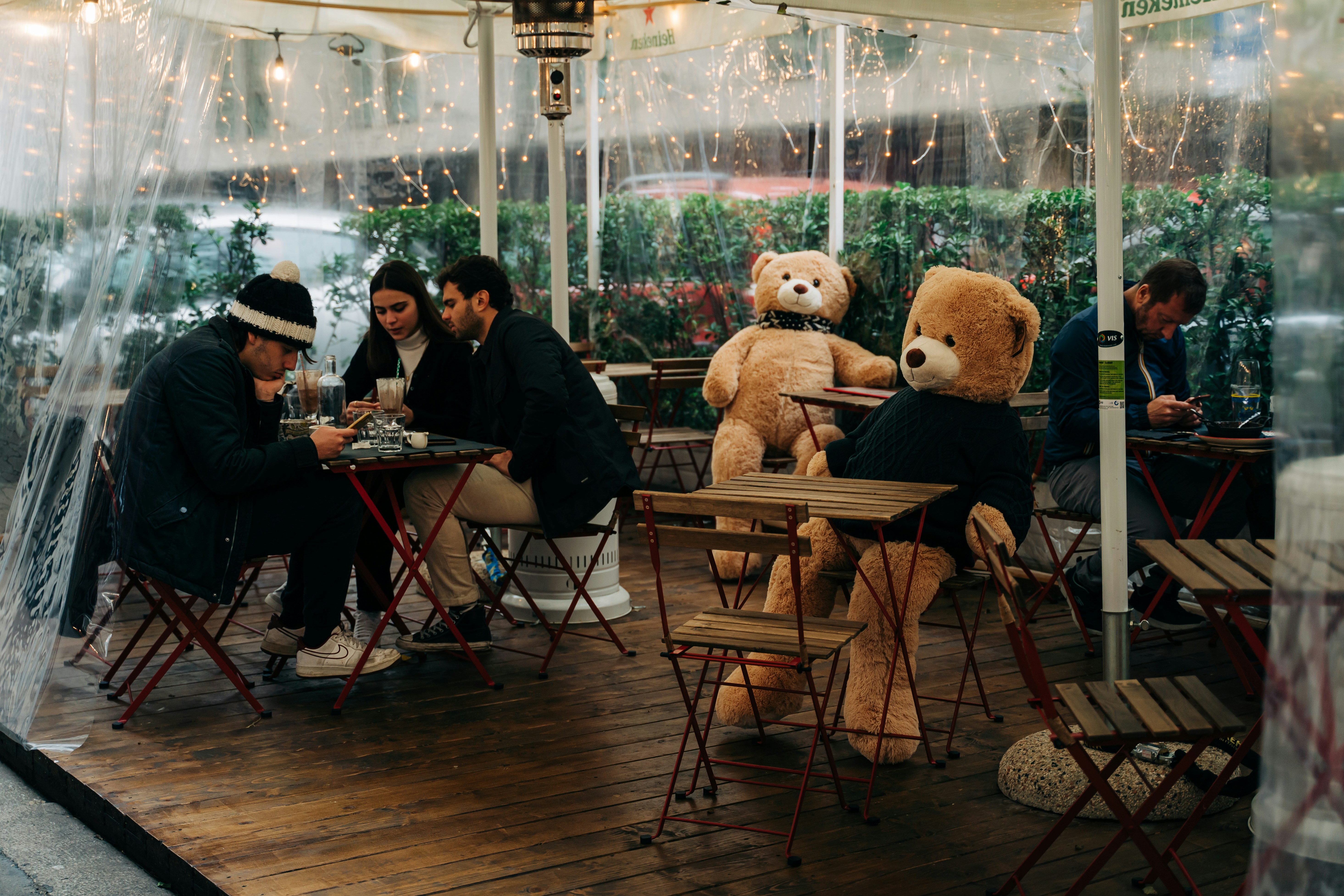 Friends having coffee in a café in Rome, Italy, where they are using giant teddy bears to enforce physical distancing rules to avoid the spread of Covid-19