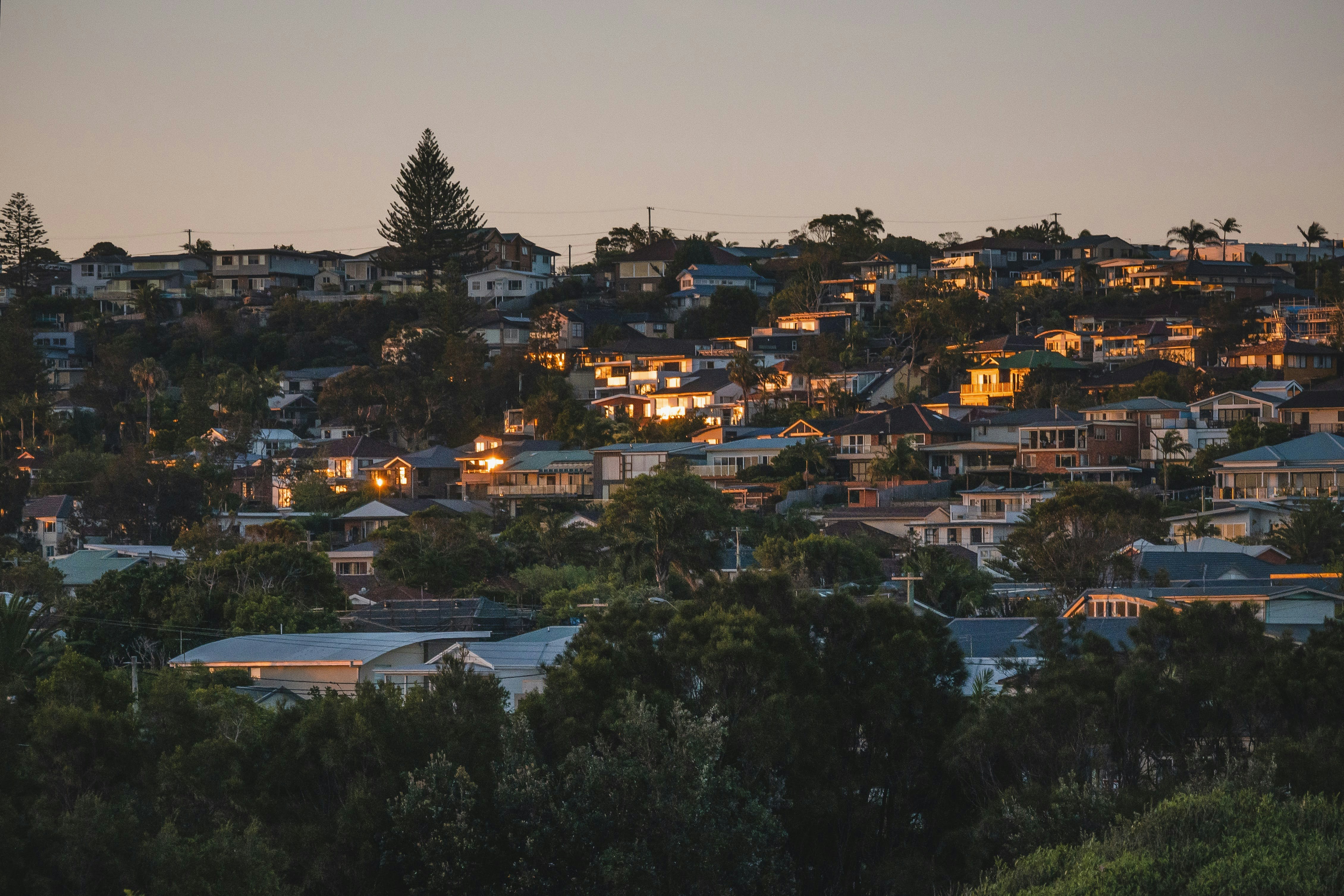 Illuminated houses dotting a hillside at twilight, showcasing the warm glow of lights against a dusky sky.