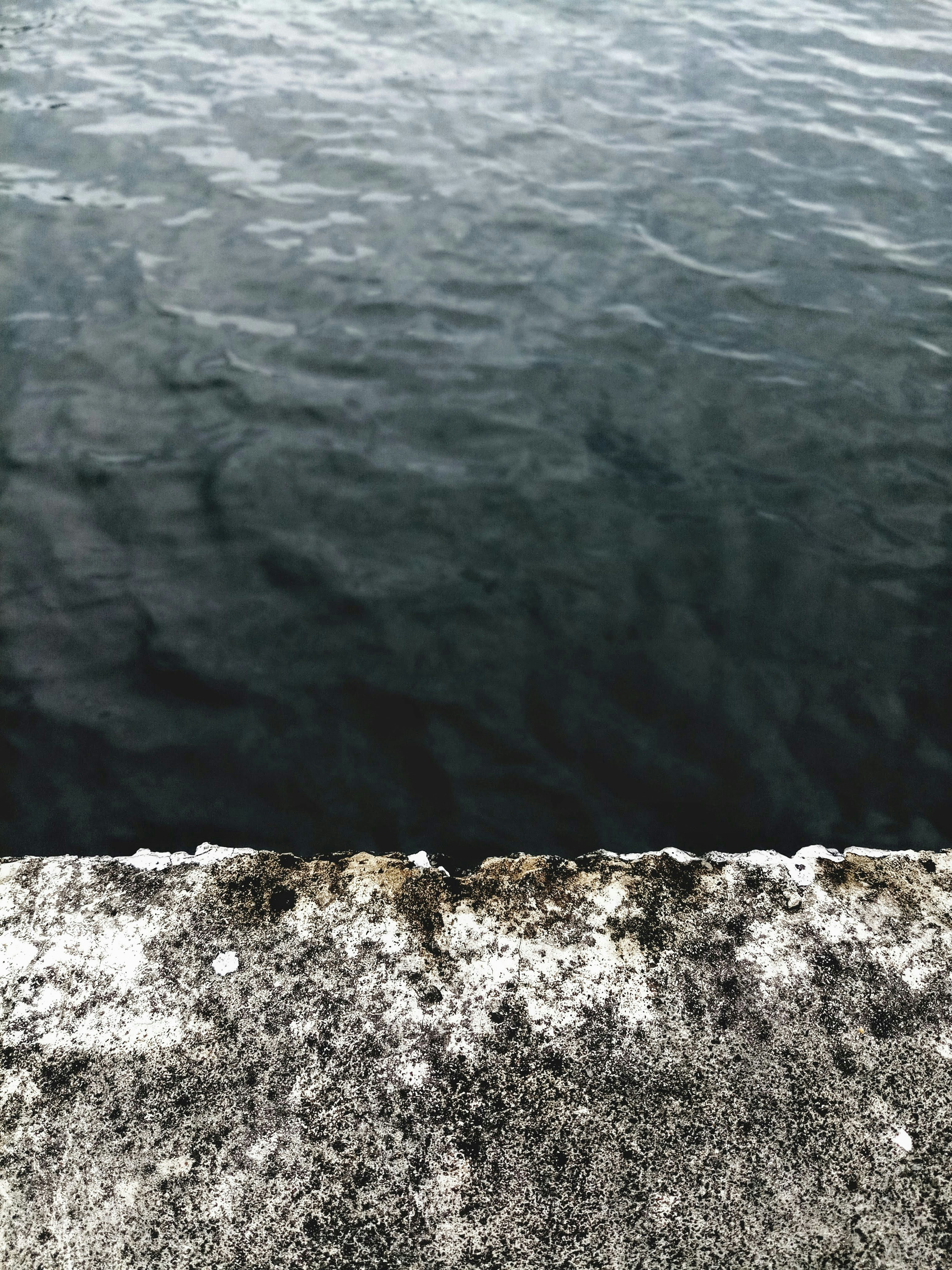 Boundary of Stone and Sea: A Weathered Pier Meets Quiet Depths