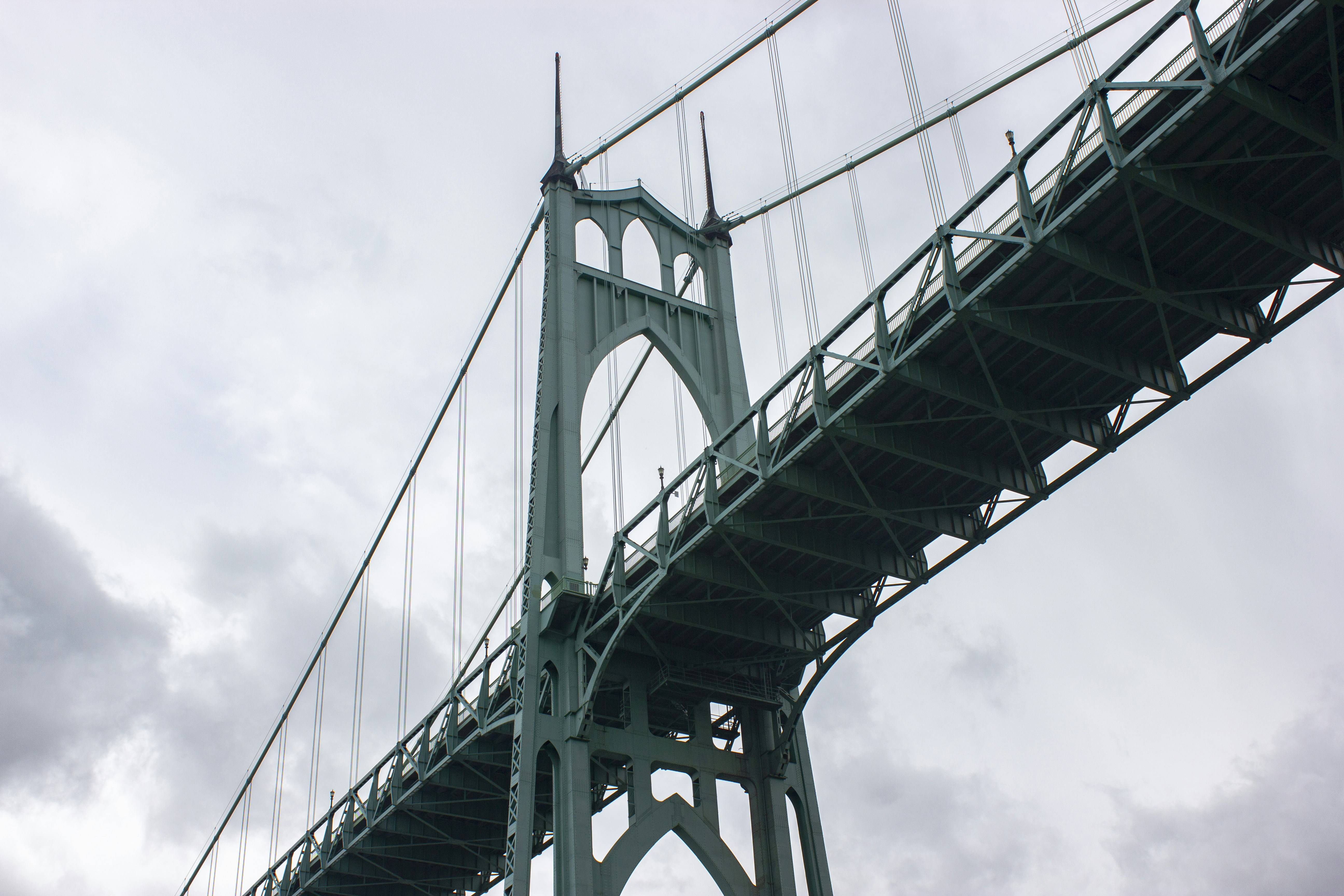 Low angle view of a bridge with intricate structure under a cloudy sky during daytime.