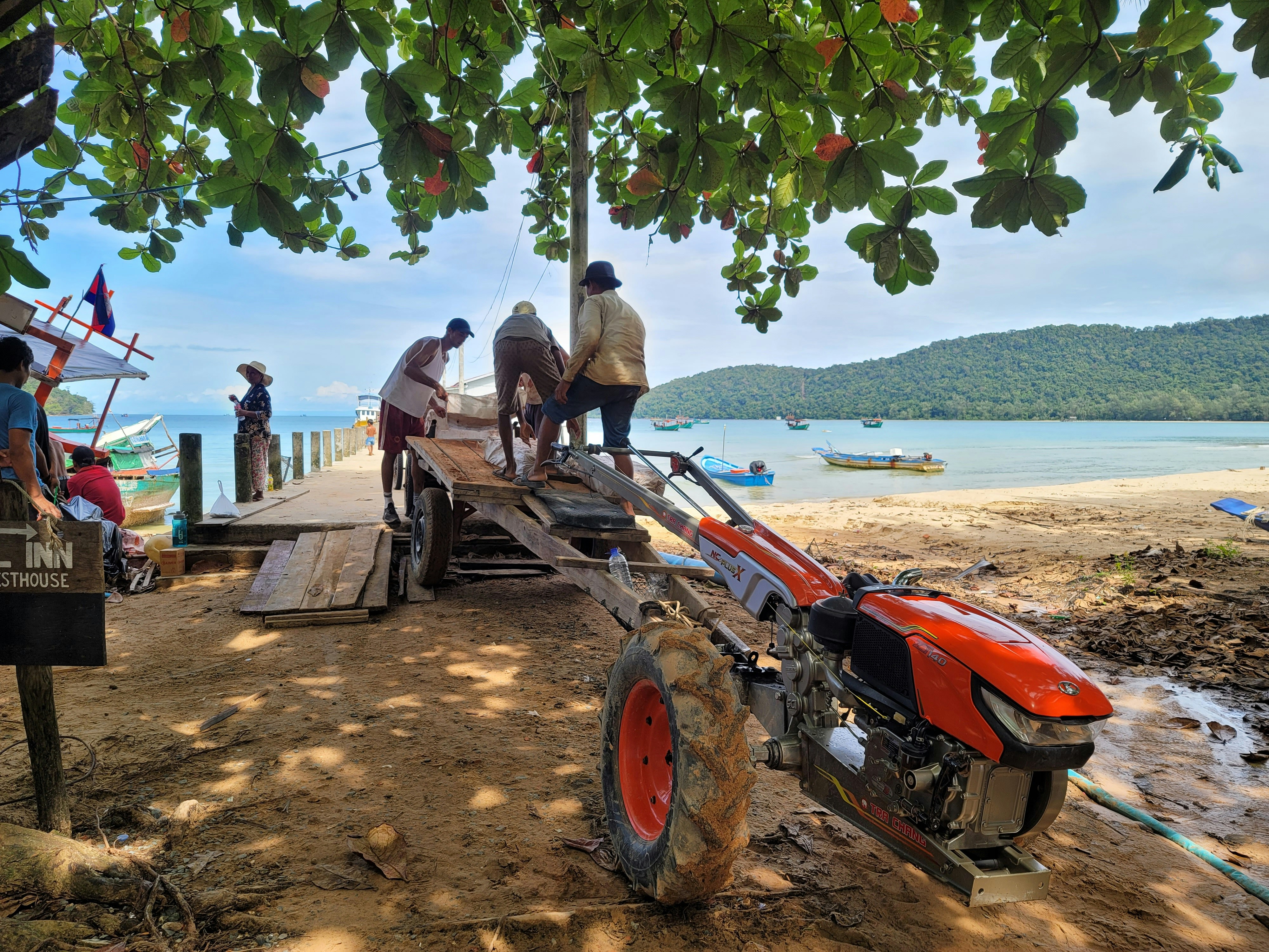 Orange Tractor on a Sunlit Beach Helps Launch a Wooden Ramp Toward a Calm Bay