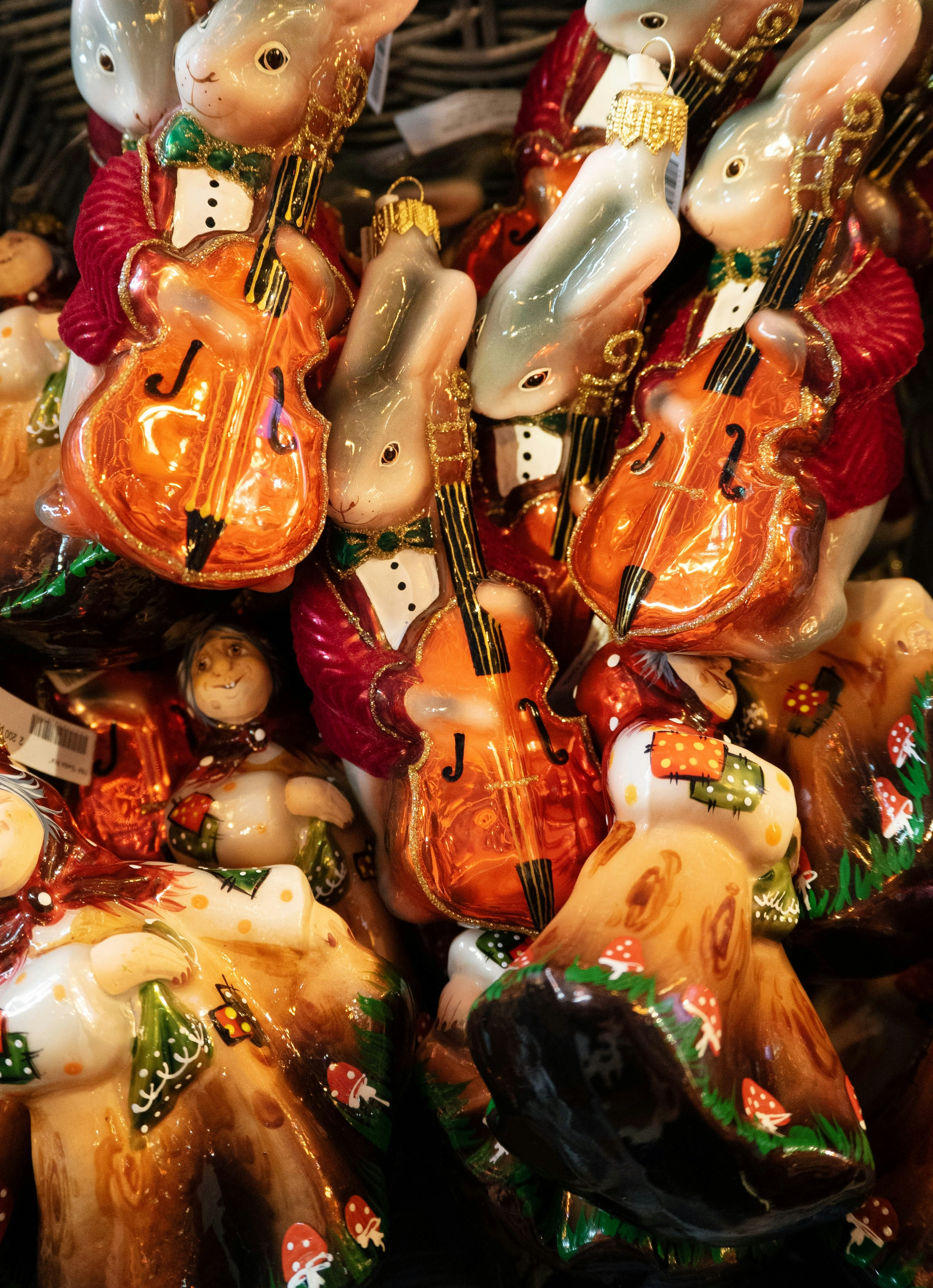 Dense cluster of glossy ceramic violin ornaments and dapper rabbit figurines in a festive holiday display.