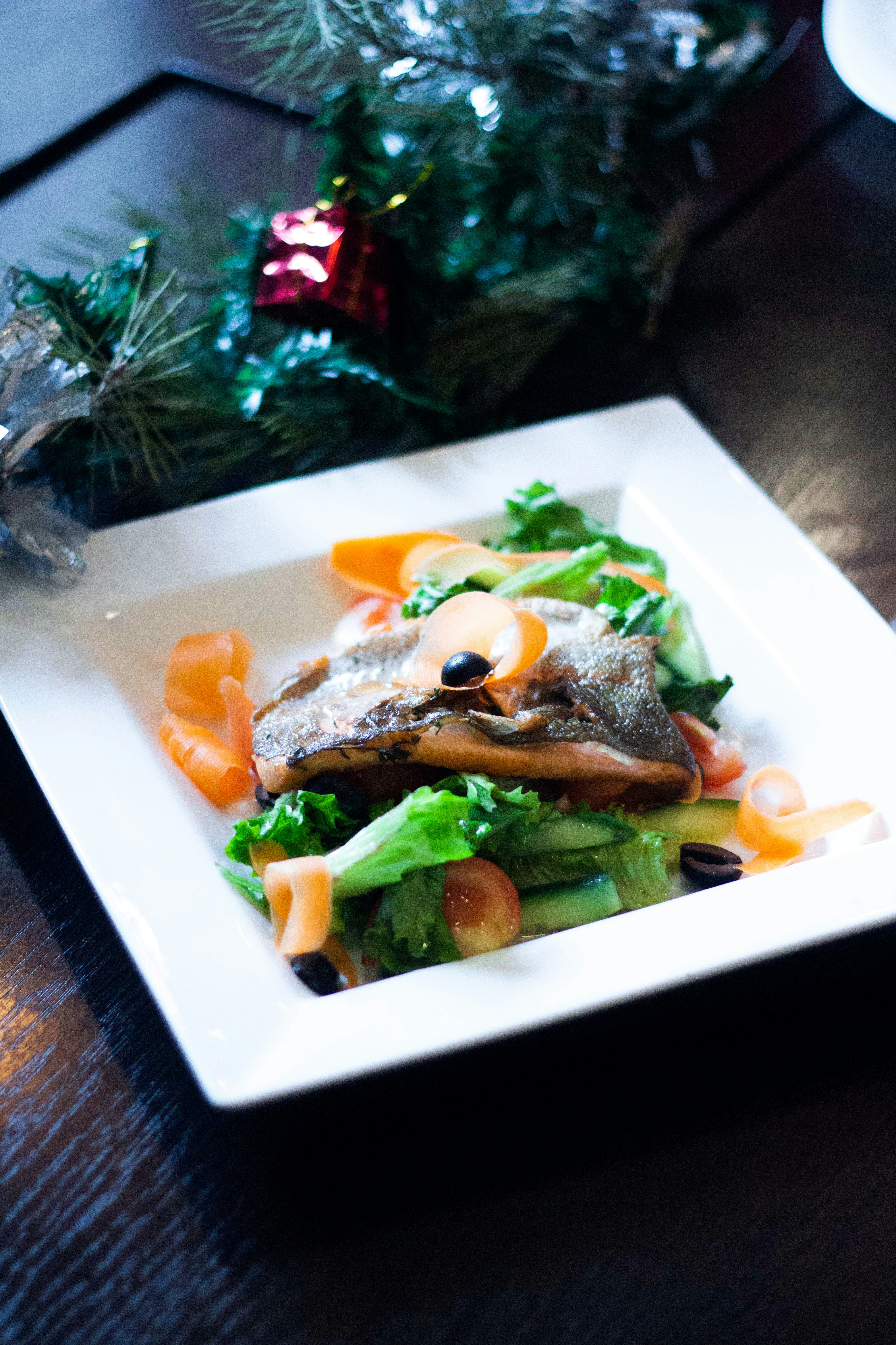 Citrus Glow: Seared Fish on a Bed of Greens under Christmas Boughs