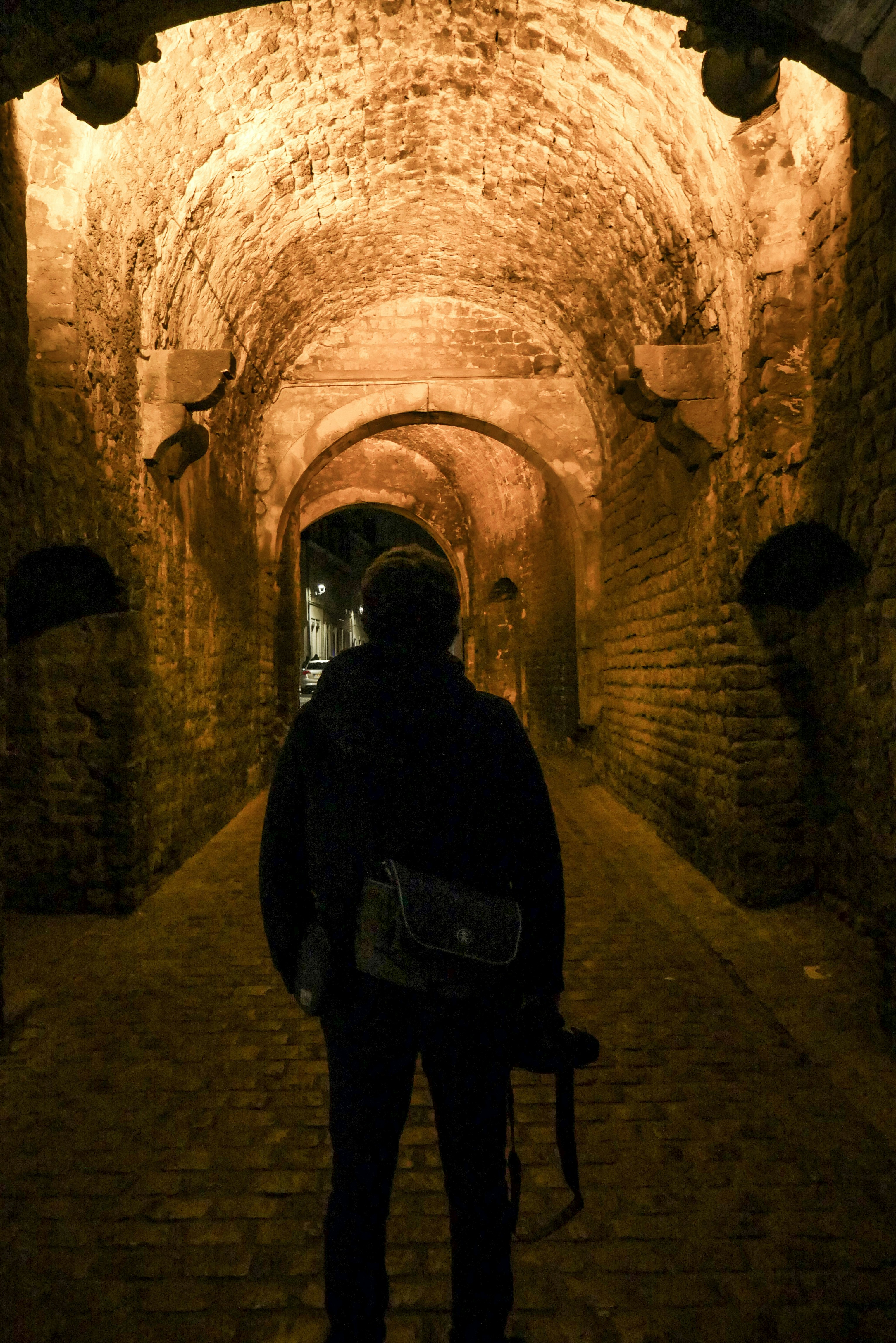 Ember-Lit Passage: A Silent Figure Within the Brick-Arch Tunnel