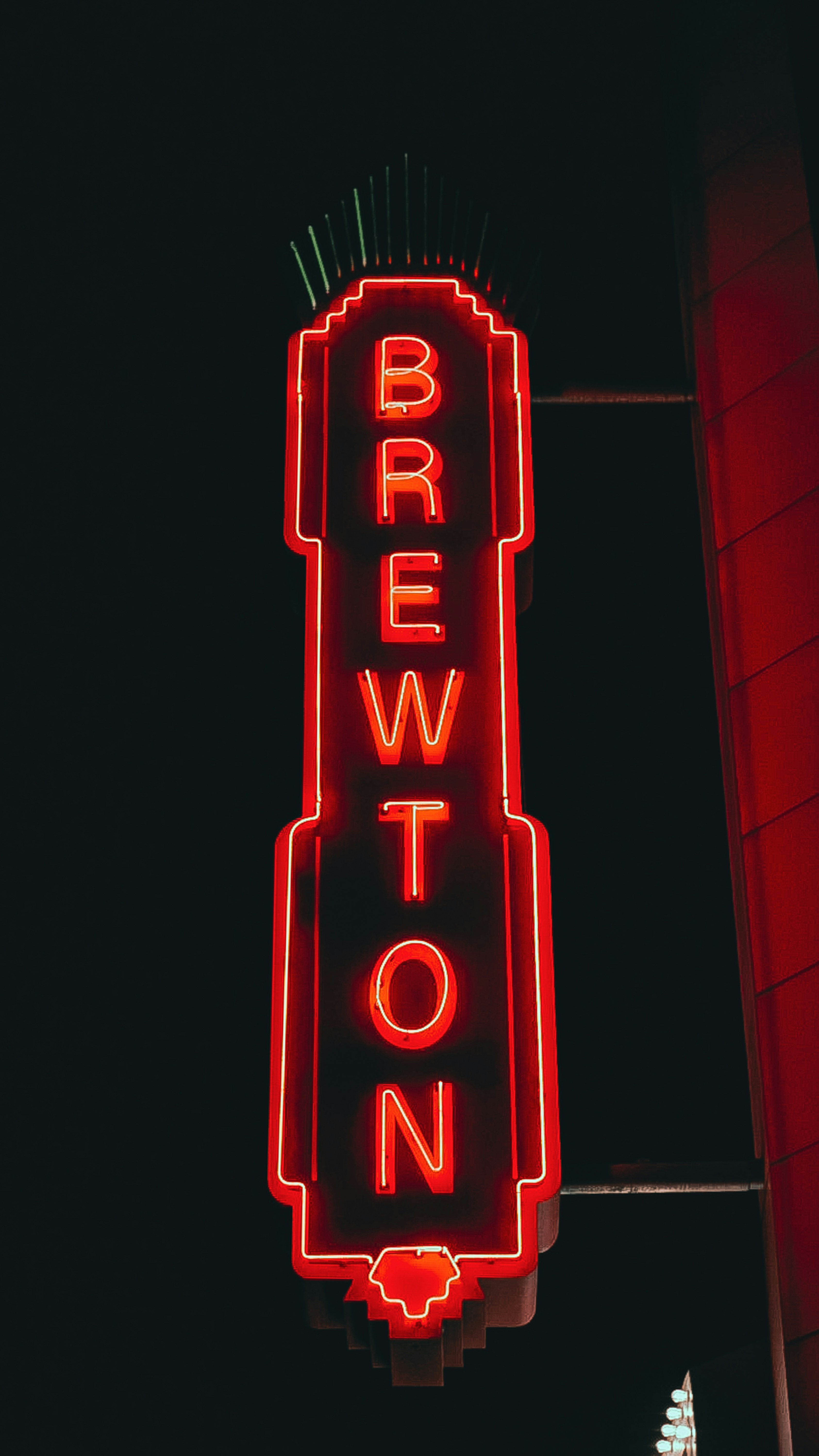 Bright neon sign reading 'BREWTON' against a dark background, highlighting vintage style and urban charm.