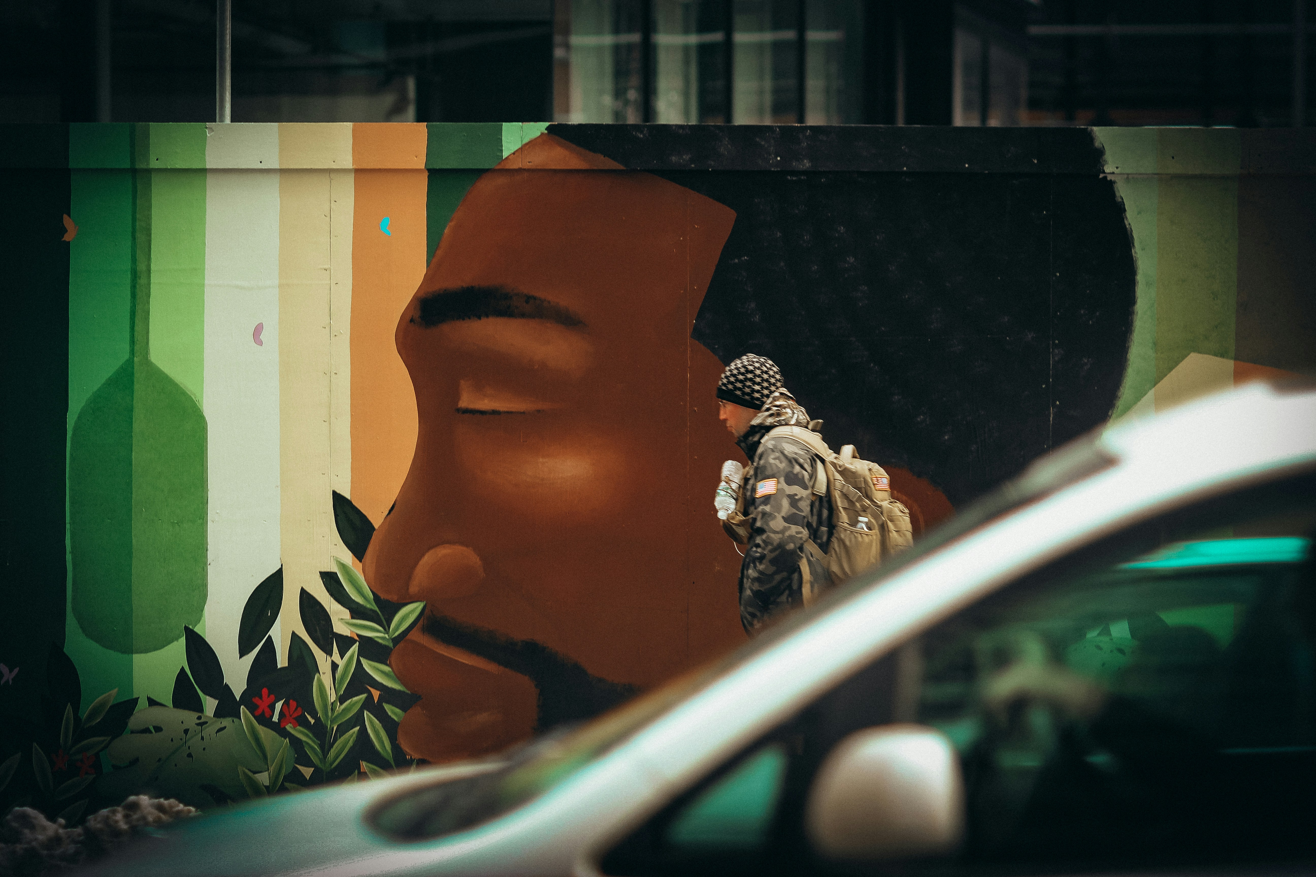 Between Brushstrokes and Boots: A Camouflaged Figure Before a Monumental Mural