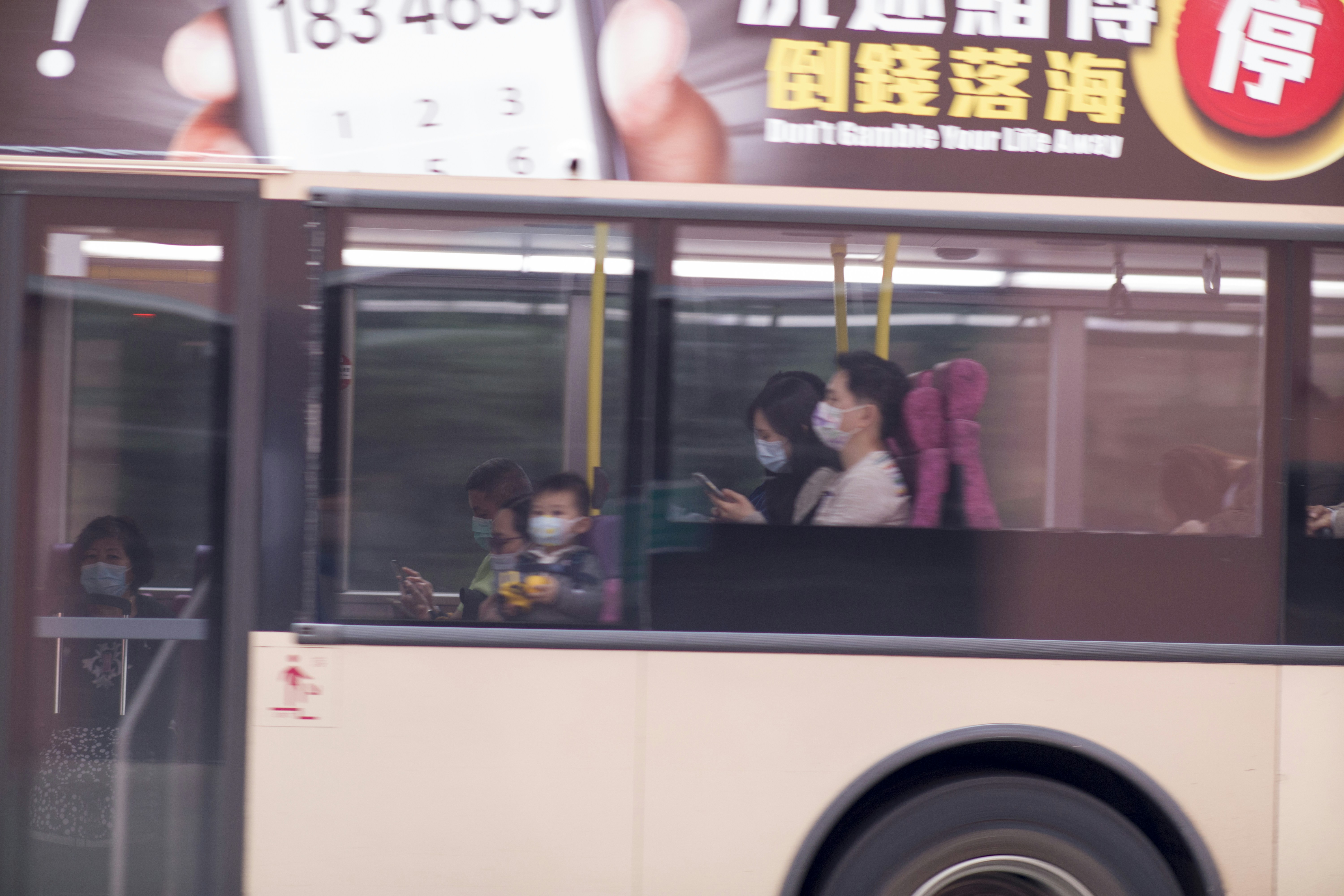 Passengers aboard a city bus, each absorbed in their own world, with masks on. The bus's motion blurs the background, emphasizing the daily commute.