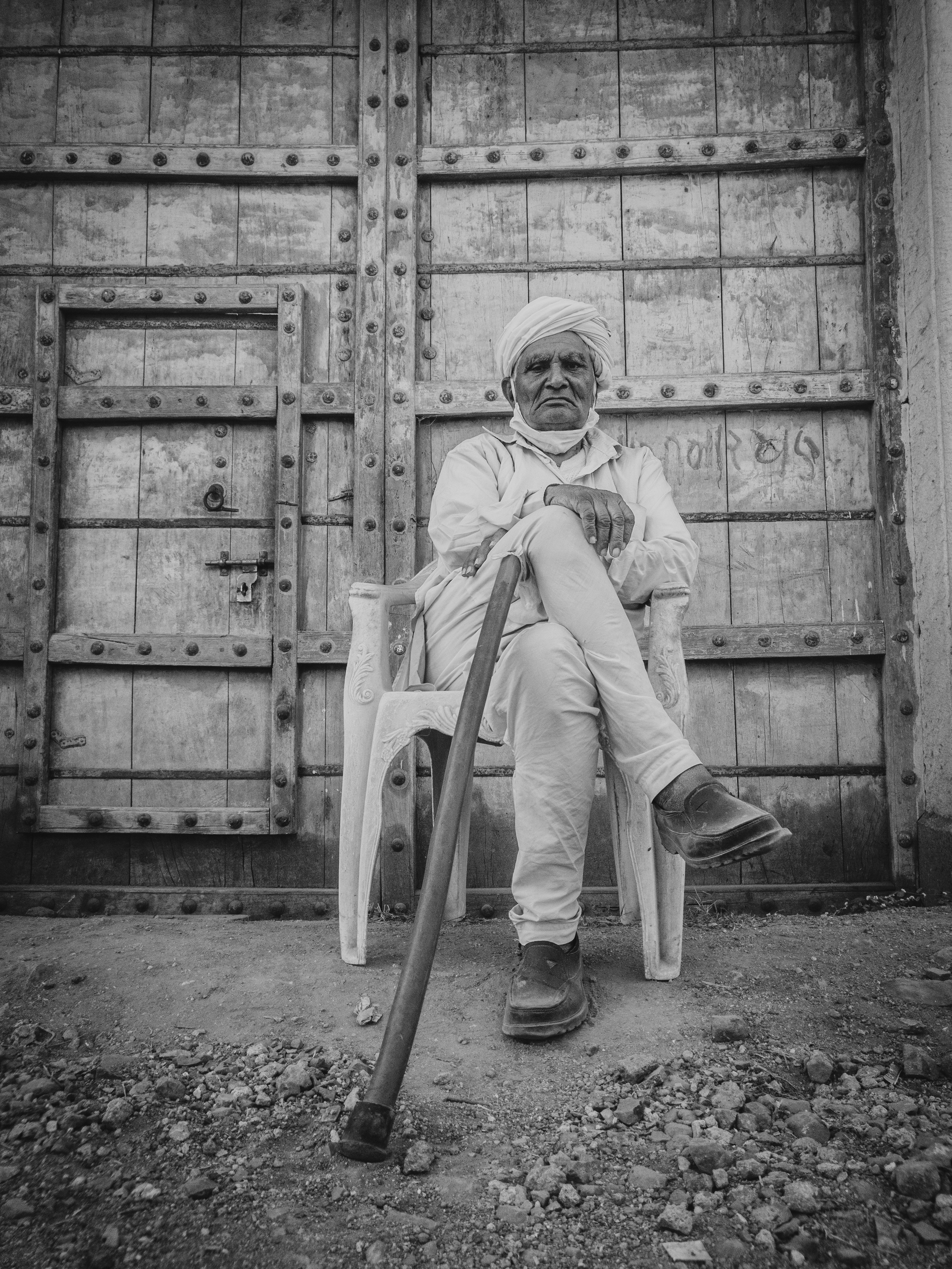 The Sentinel in Stone: A Man with a Cane on a Weathered Threshold