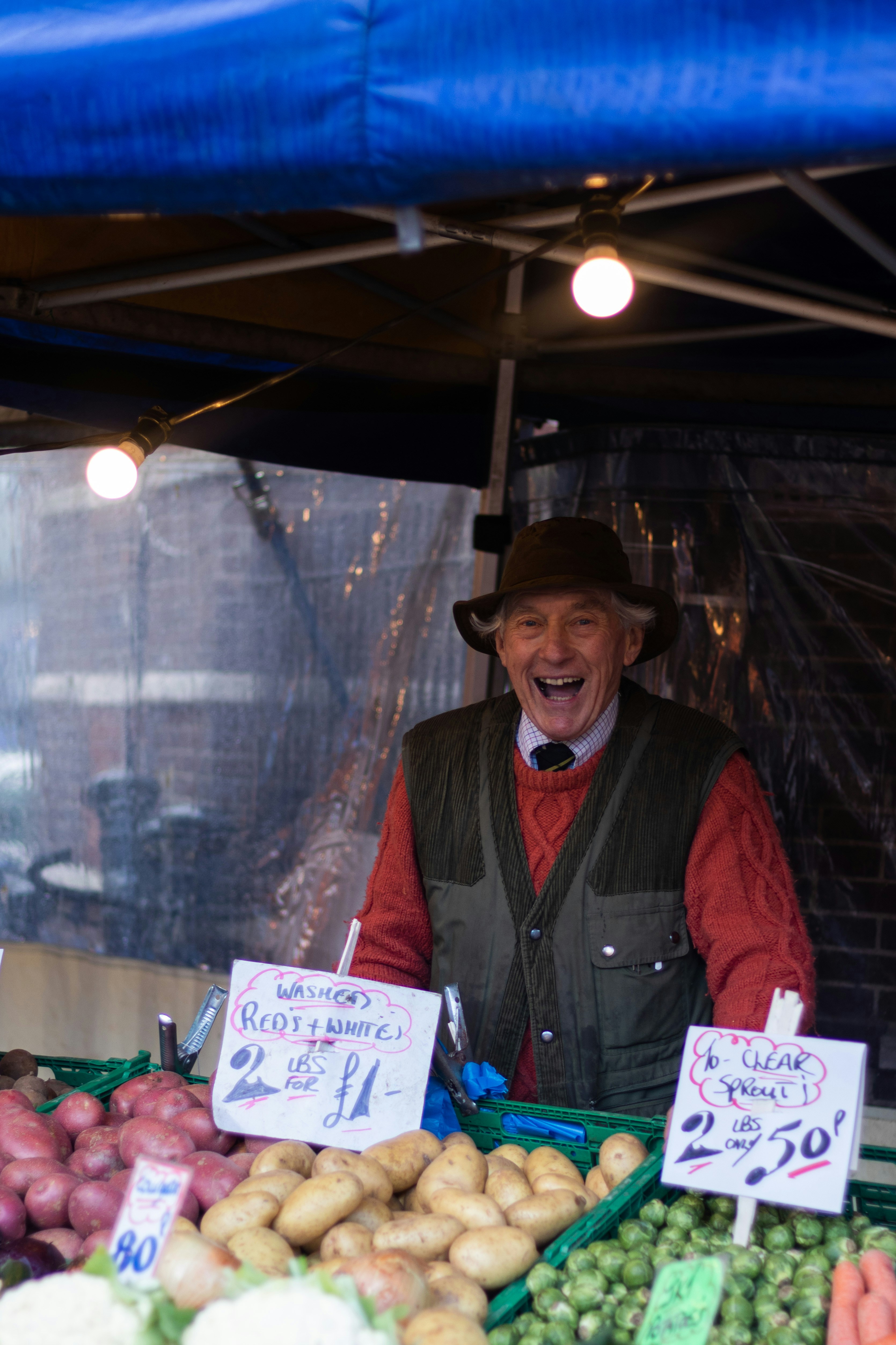 Market Vendor with Warm Smile Beneath a Canopy