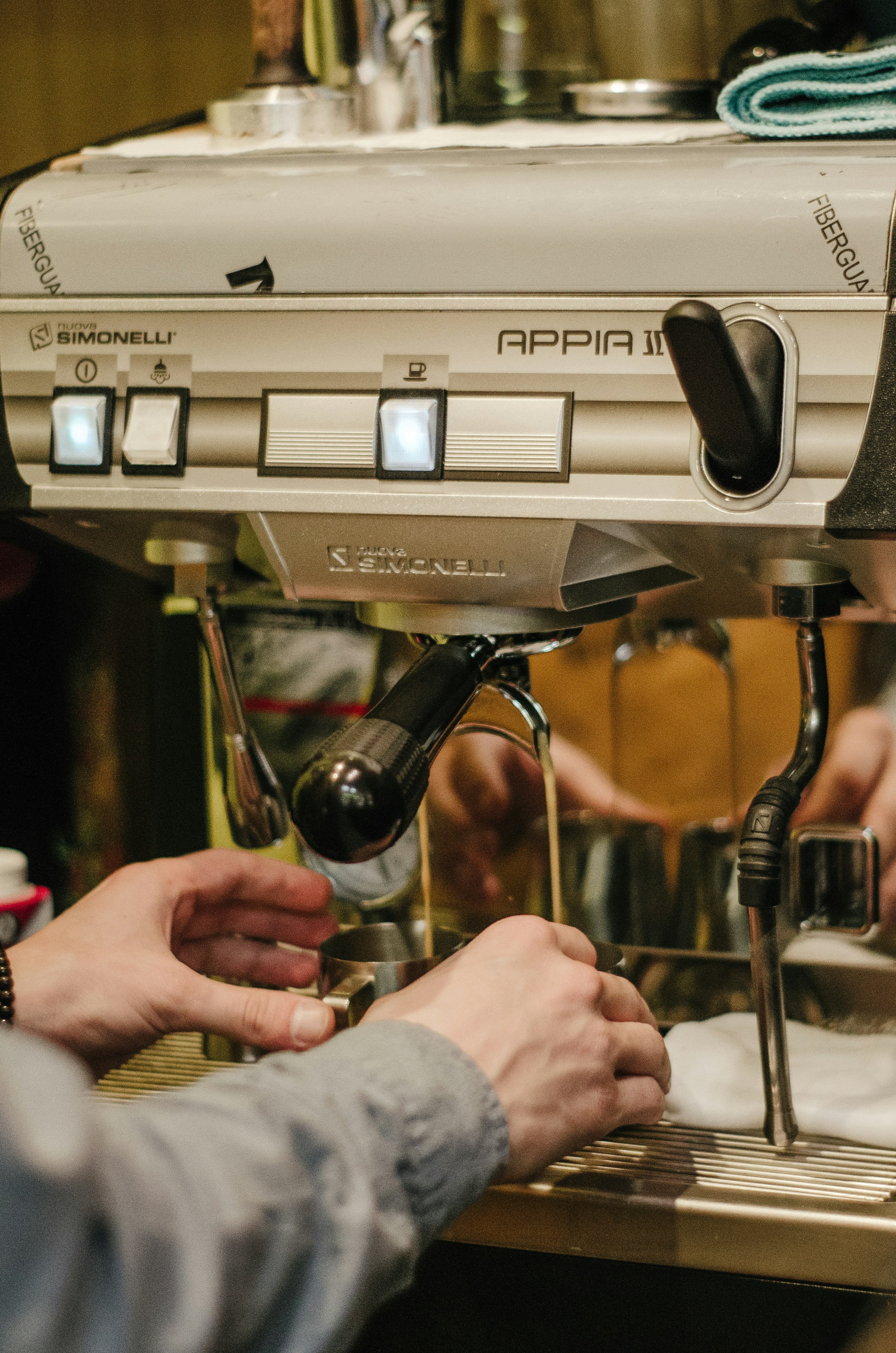 Barista at Work: Hands Guiding a Portafilter Under a Commercial Espresso Machine