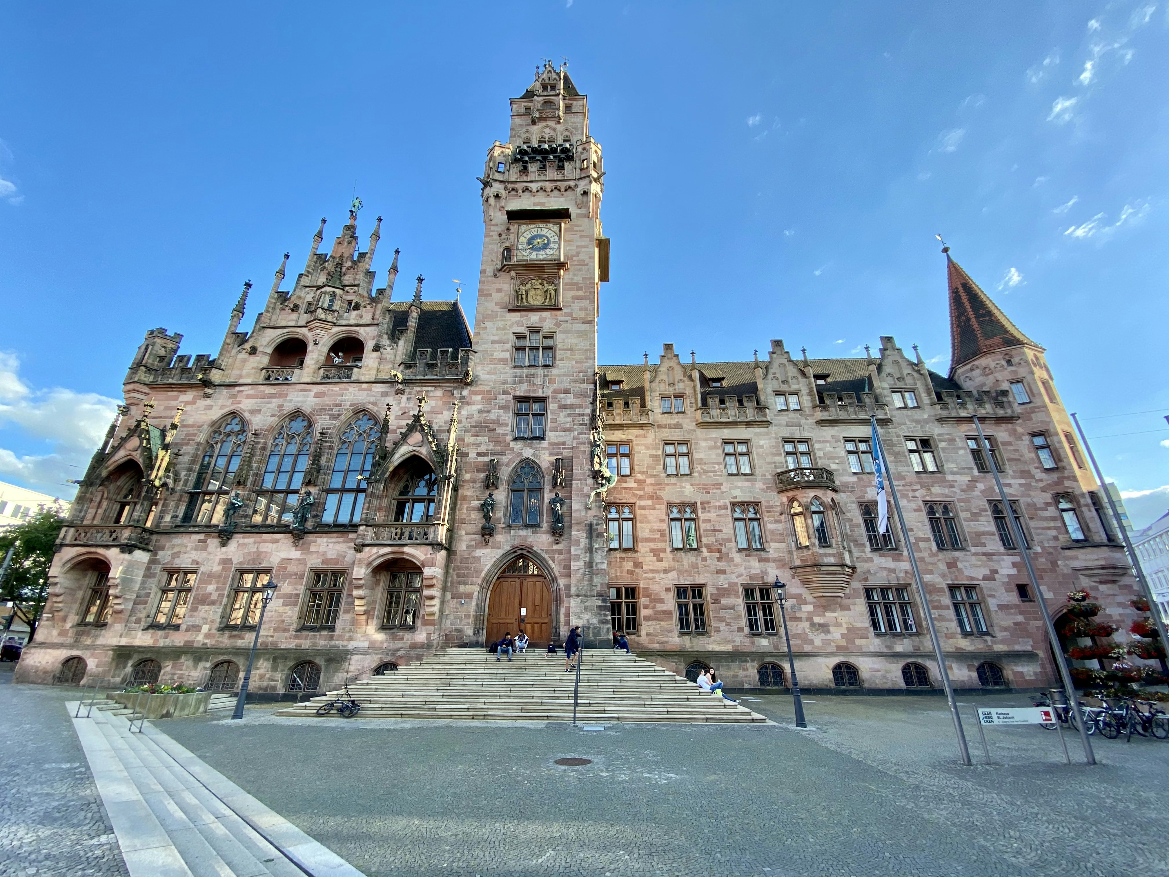 Ornate neo-Gothic city hall with detailed stonework under a clear blue sky.